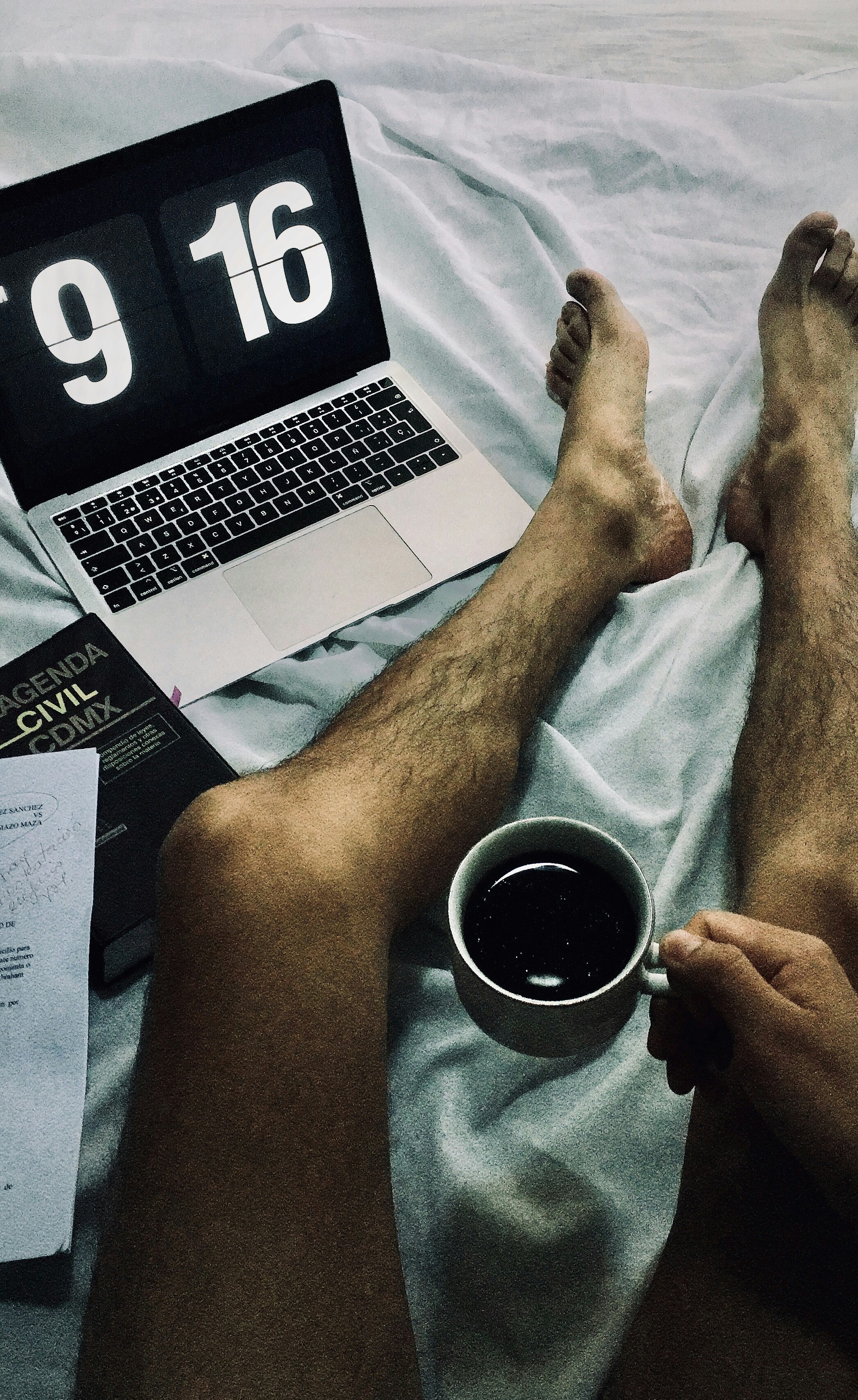 Morning Stillness: Coffee in Hand, Laptop Glow on Linen Bed