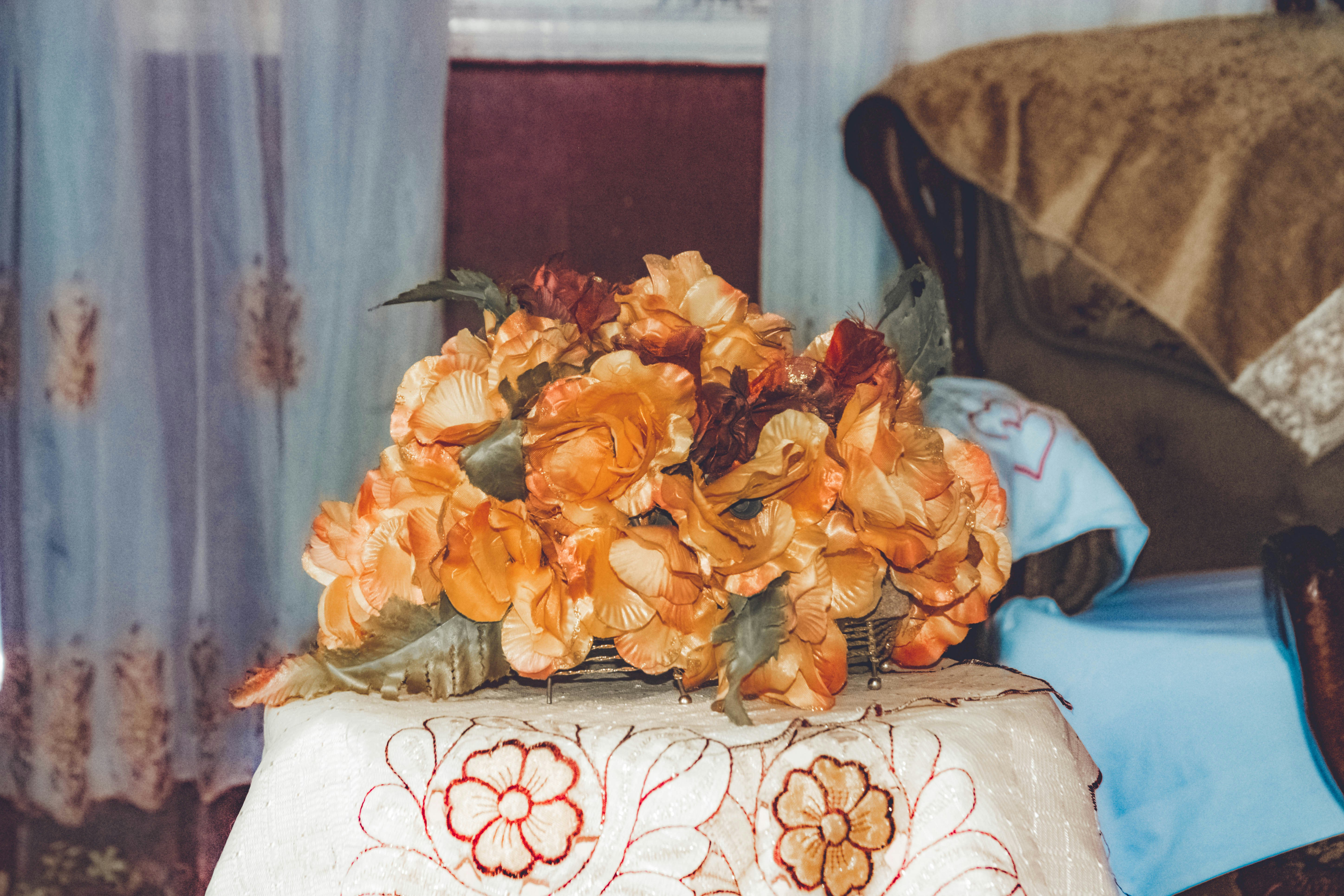 Orange Hibiscus Bouquet Resting on a Floral-stitched Table
