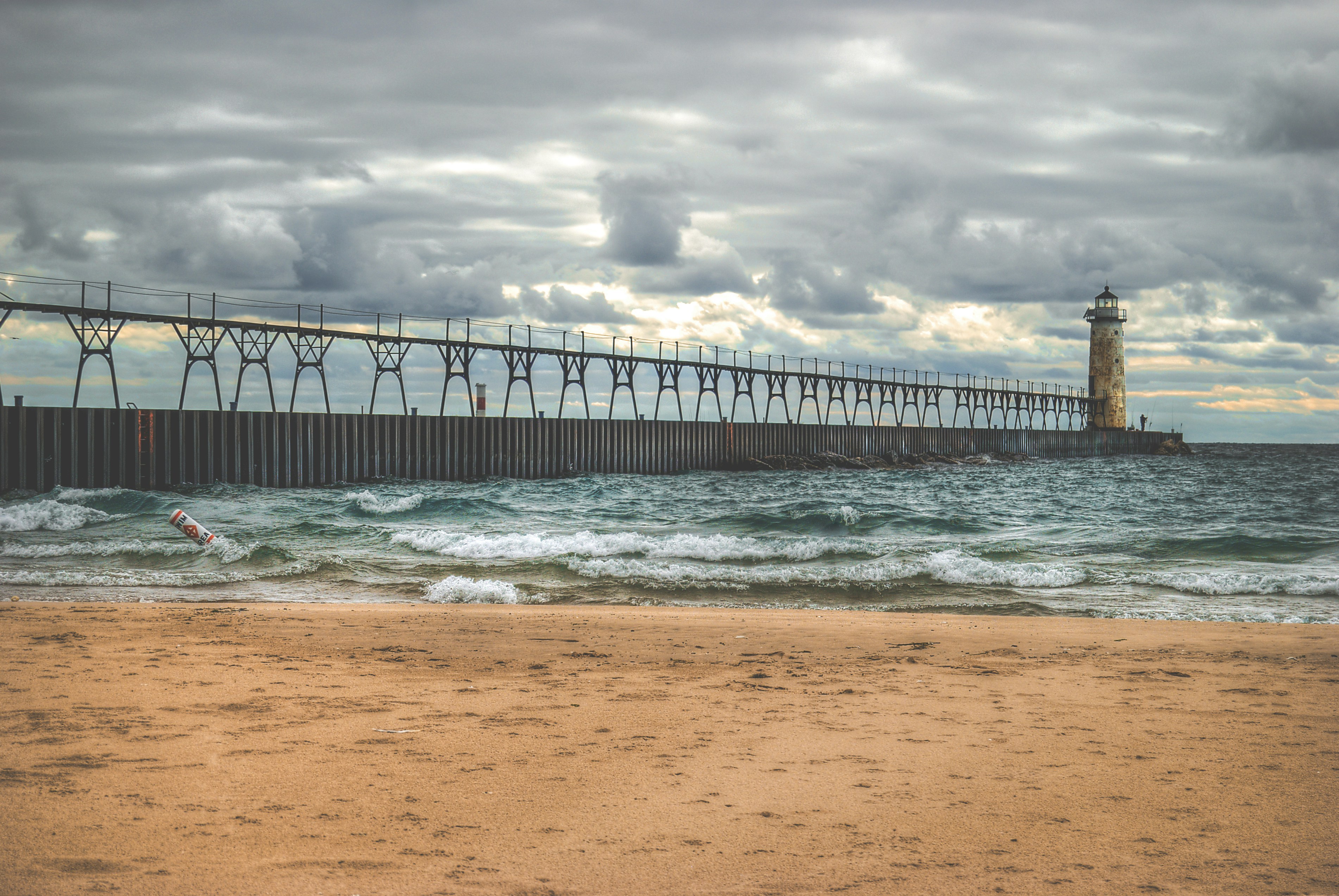 White lighthouse standing tall against a dramatic cloudy sky by the ocean.
