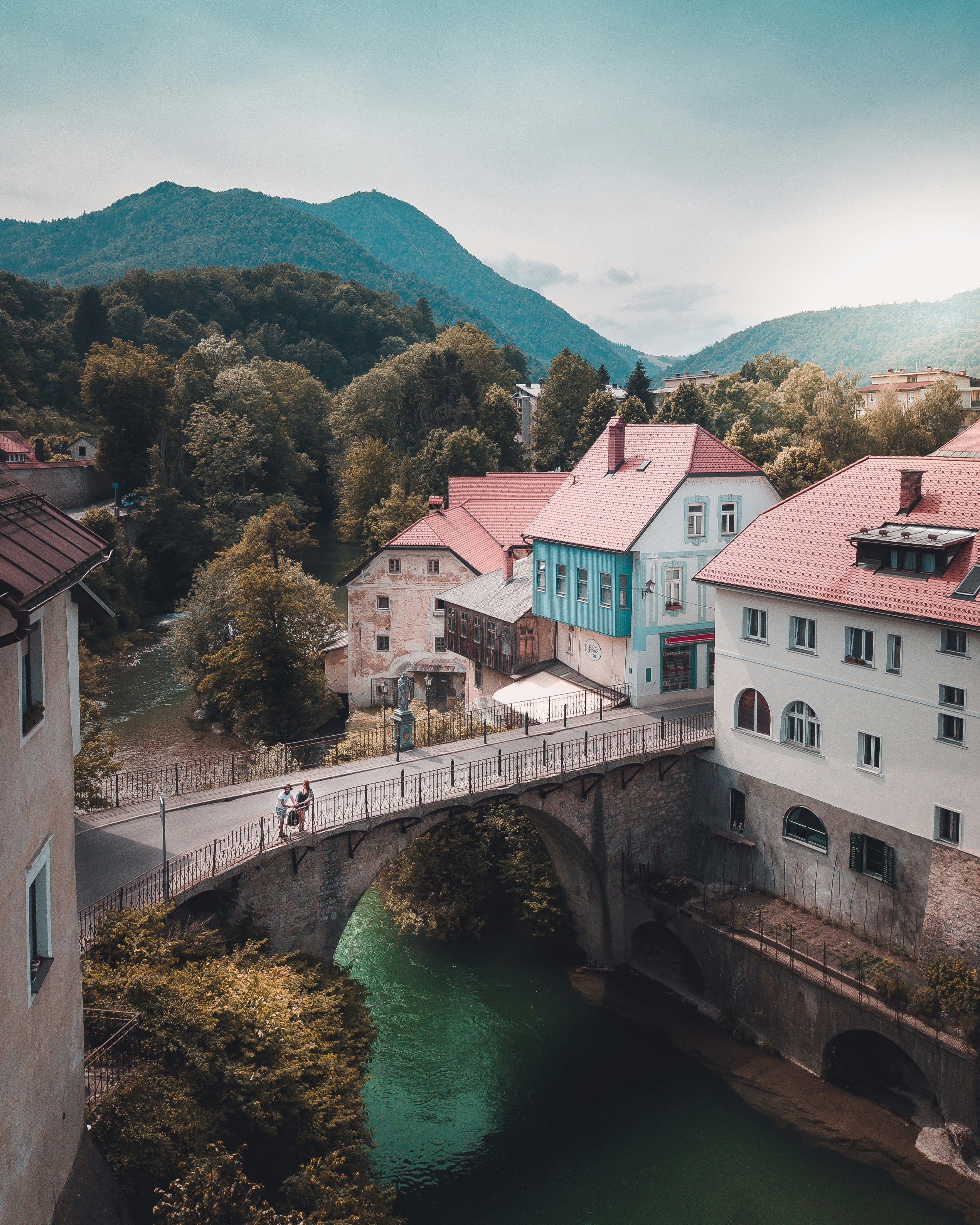 Pastel houses and a stone bridge arch over emerald water