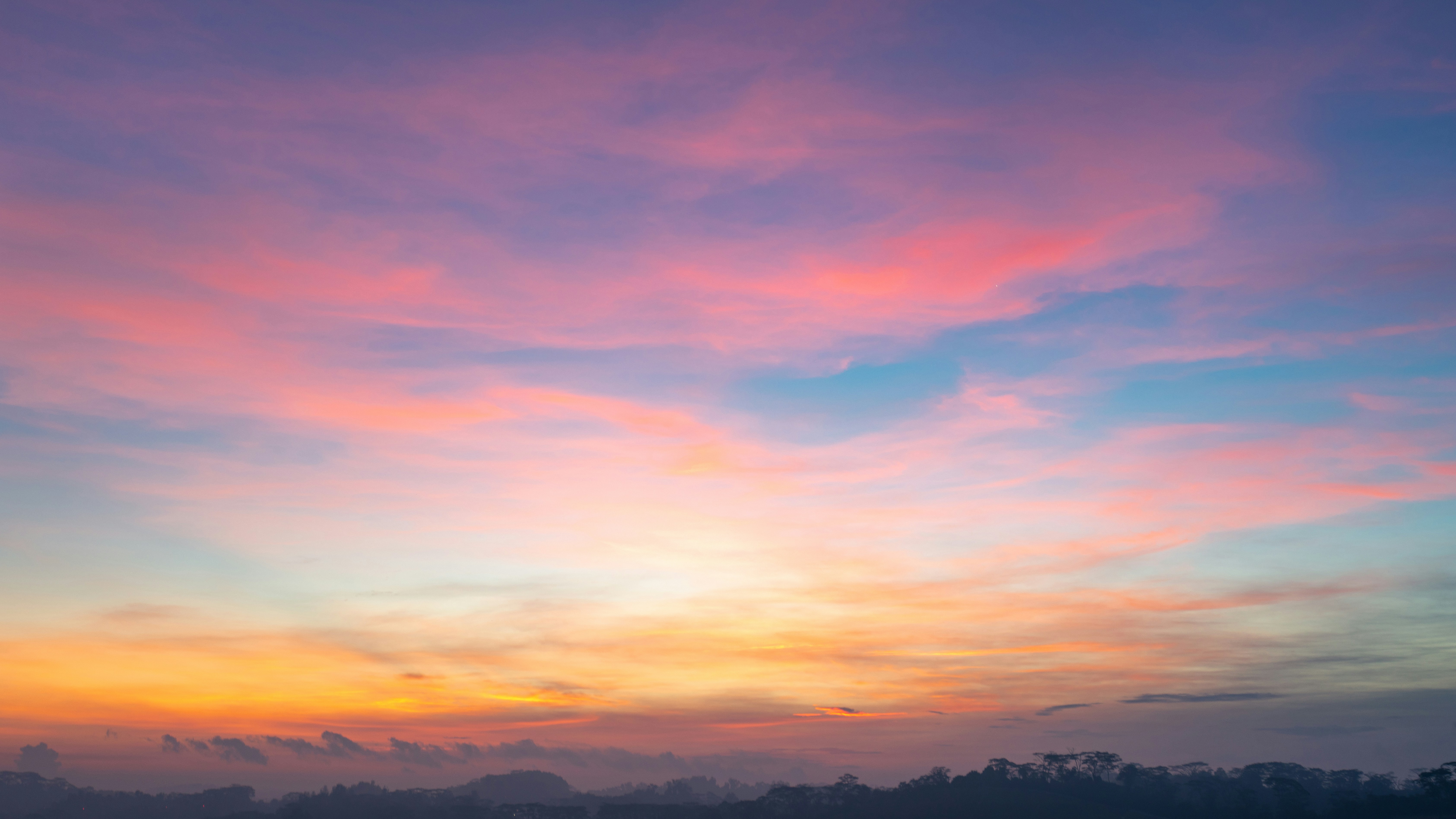 Vibrant sunrise with pink and orange hues blending across a serene sky.