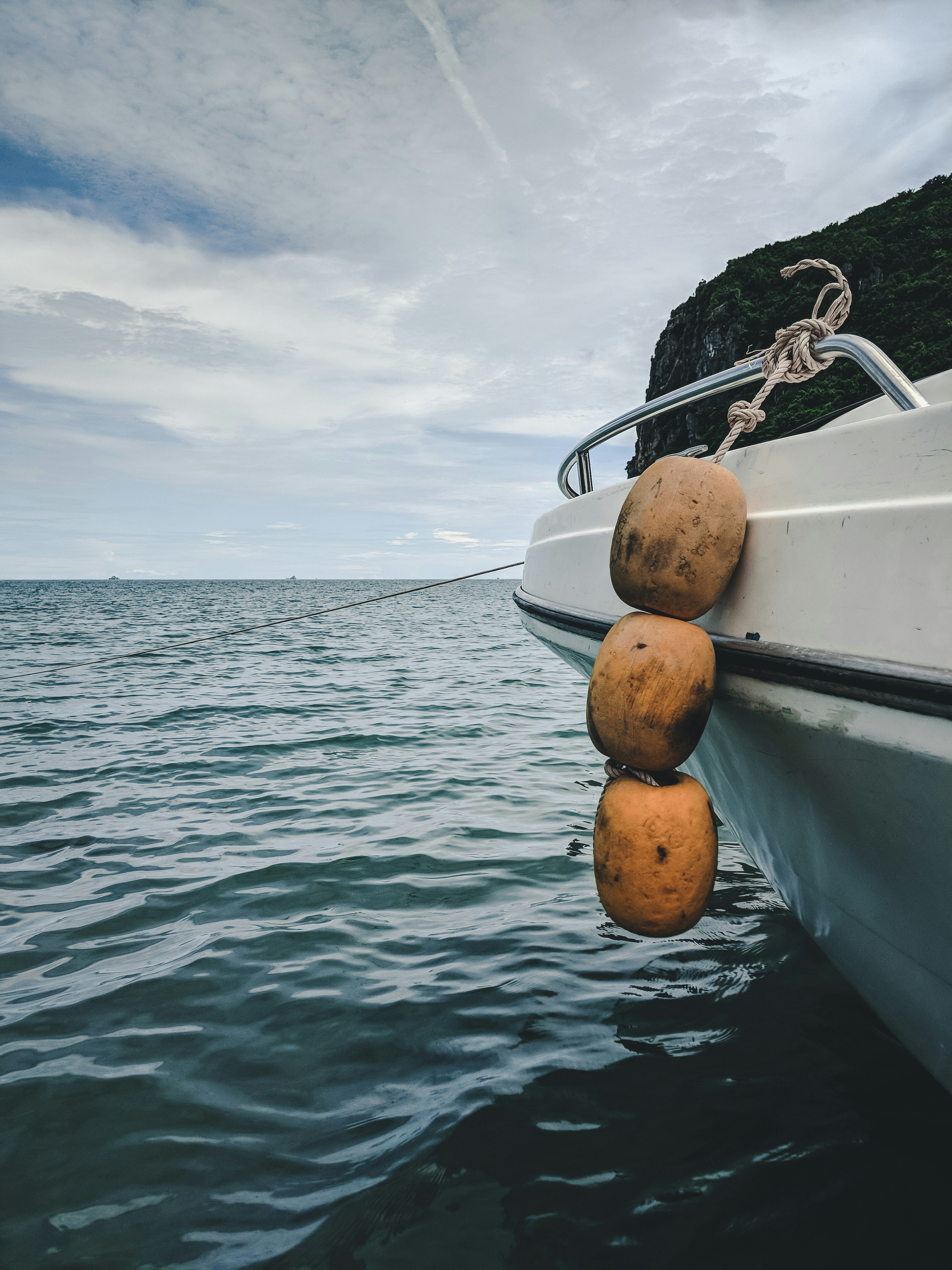Bowside Buoy Trio: Orange Spheres Cling to a White Vessel at Sea