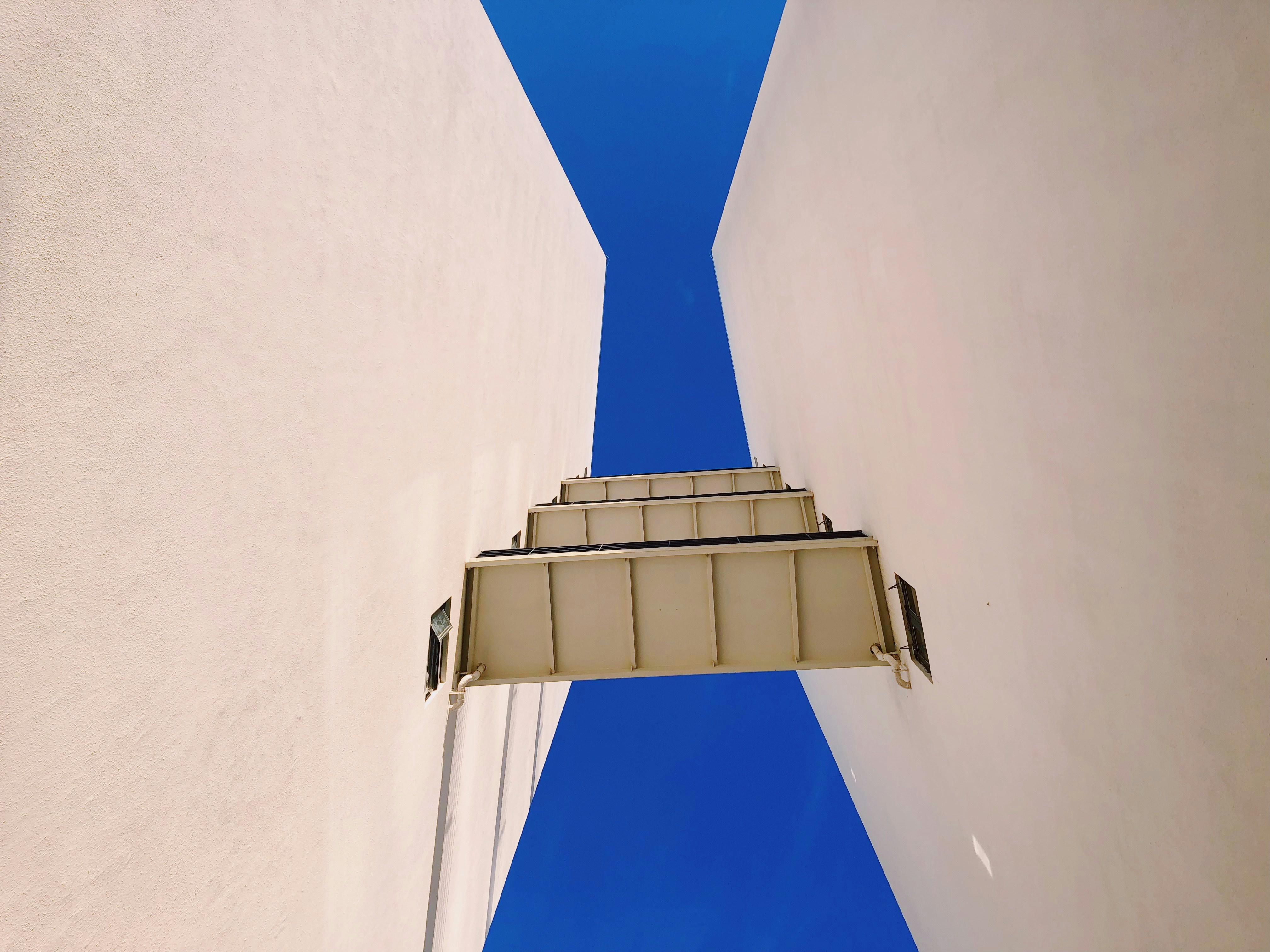 Azure Sky Through Architectural Crease: A Staircase Frame Framed by Walls