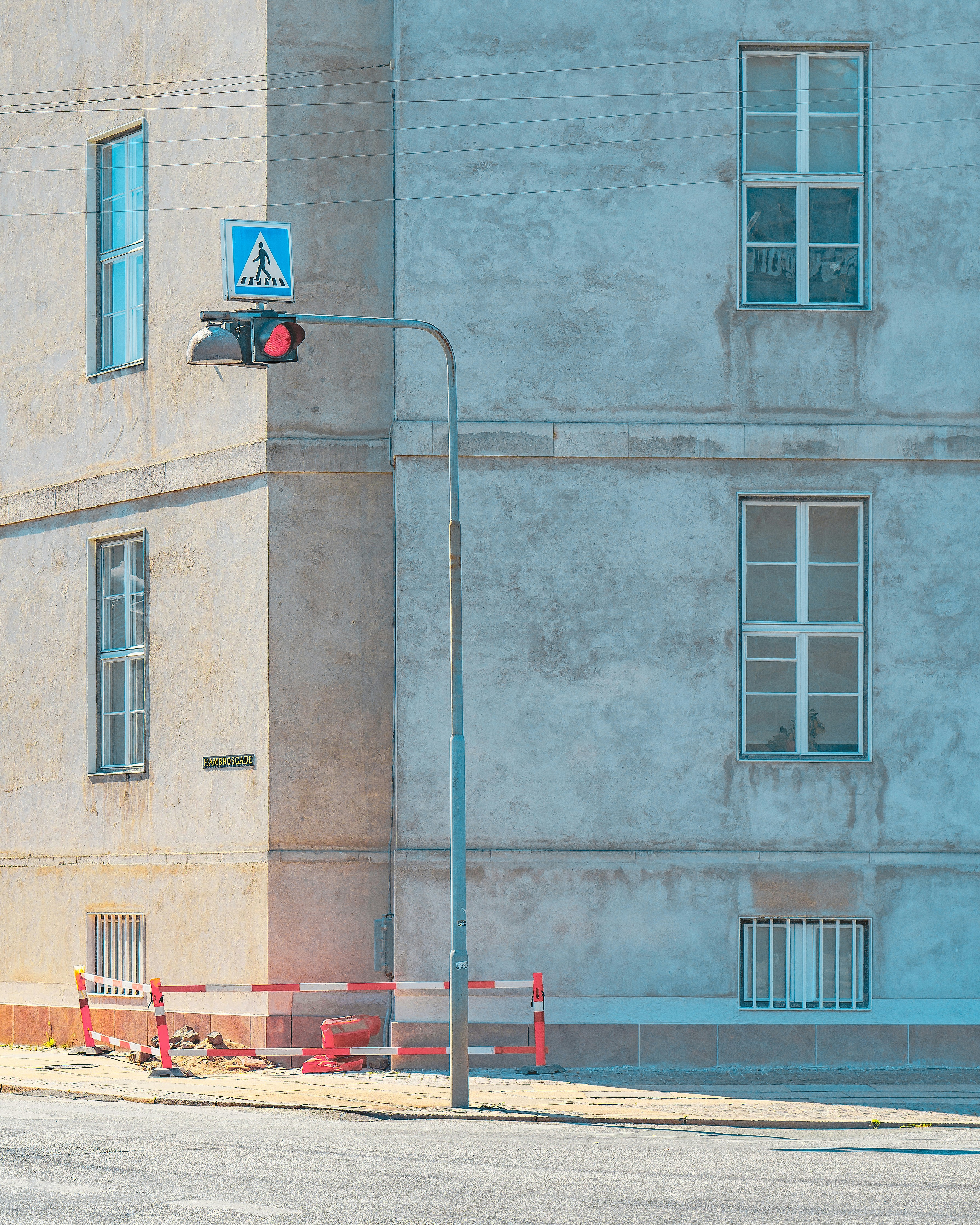 Traffic light and pedestrian sign juxtaposed against a textured building facade, highlighting urban design elements.