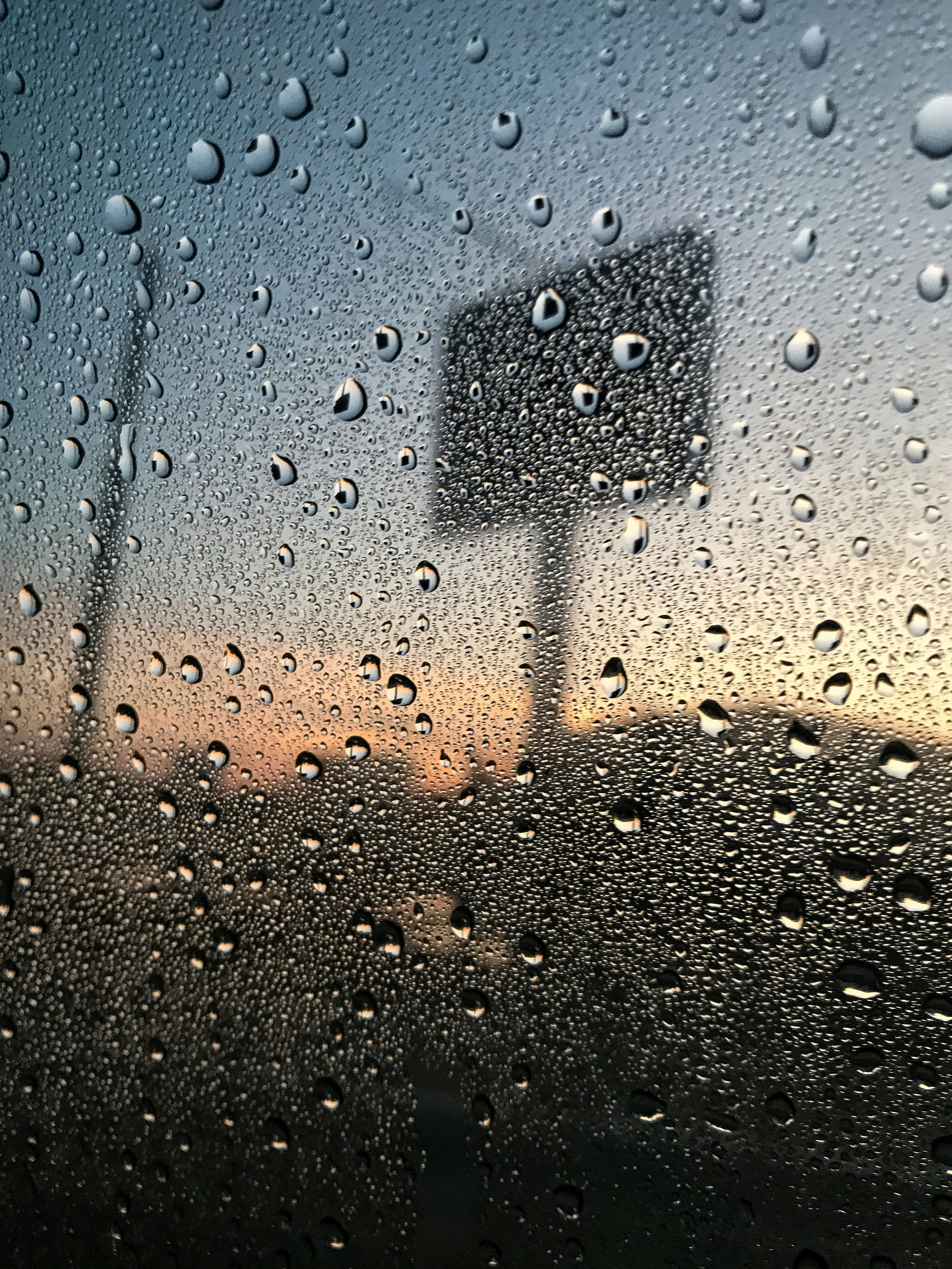 Rain-kissed stadium glass: droplets framing a distant boardlight glow