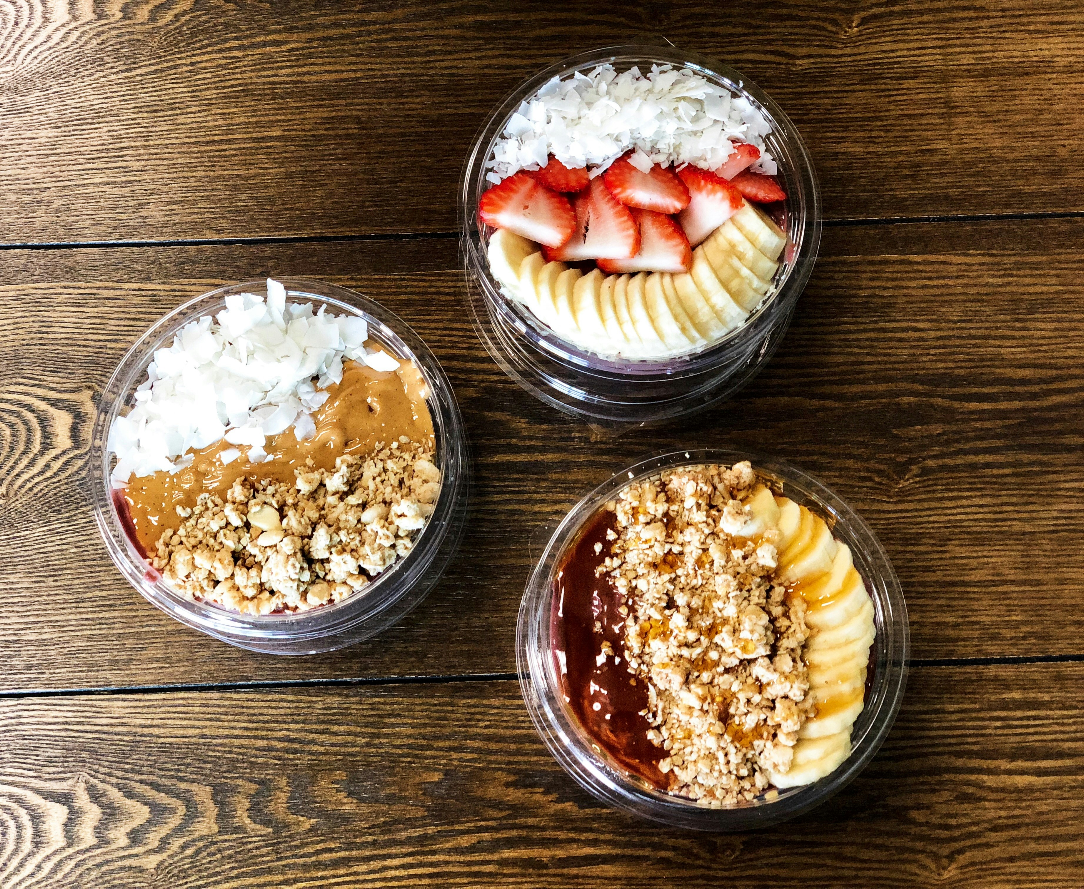 Fruit-and-granola Trio: A Rustic Wooden Display of Smoothie Bowls
