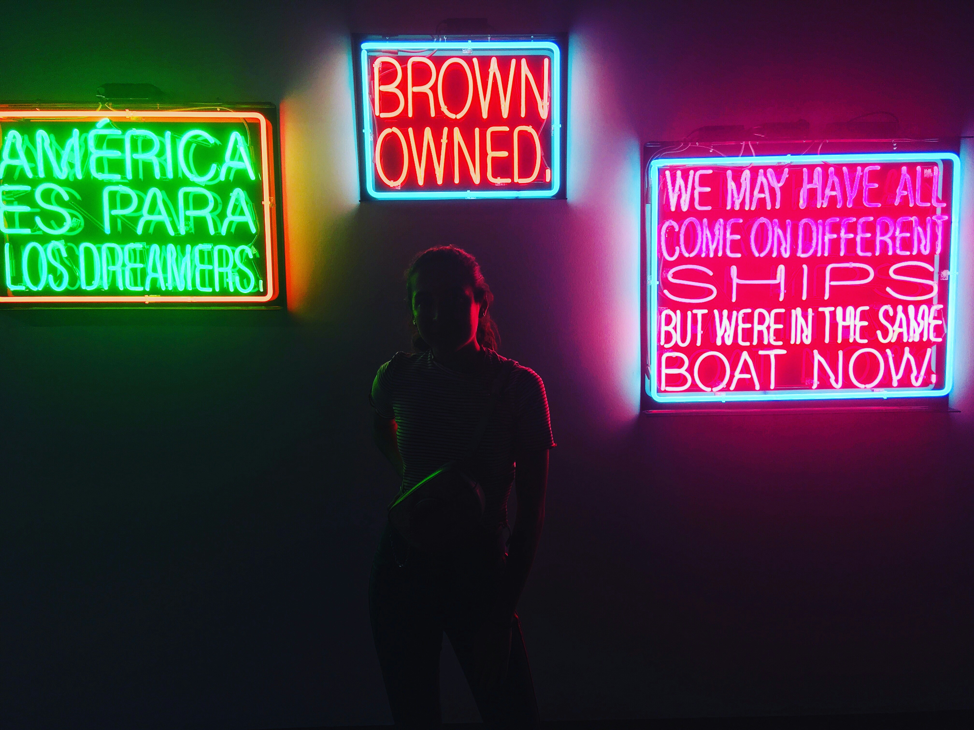 Neon Triad: A Silhouette Standing Between Electric Signs