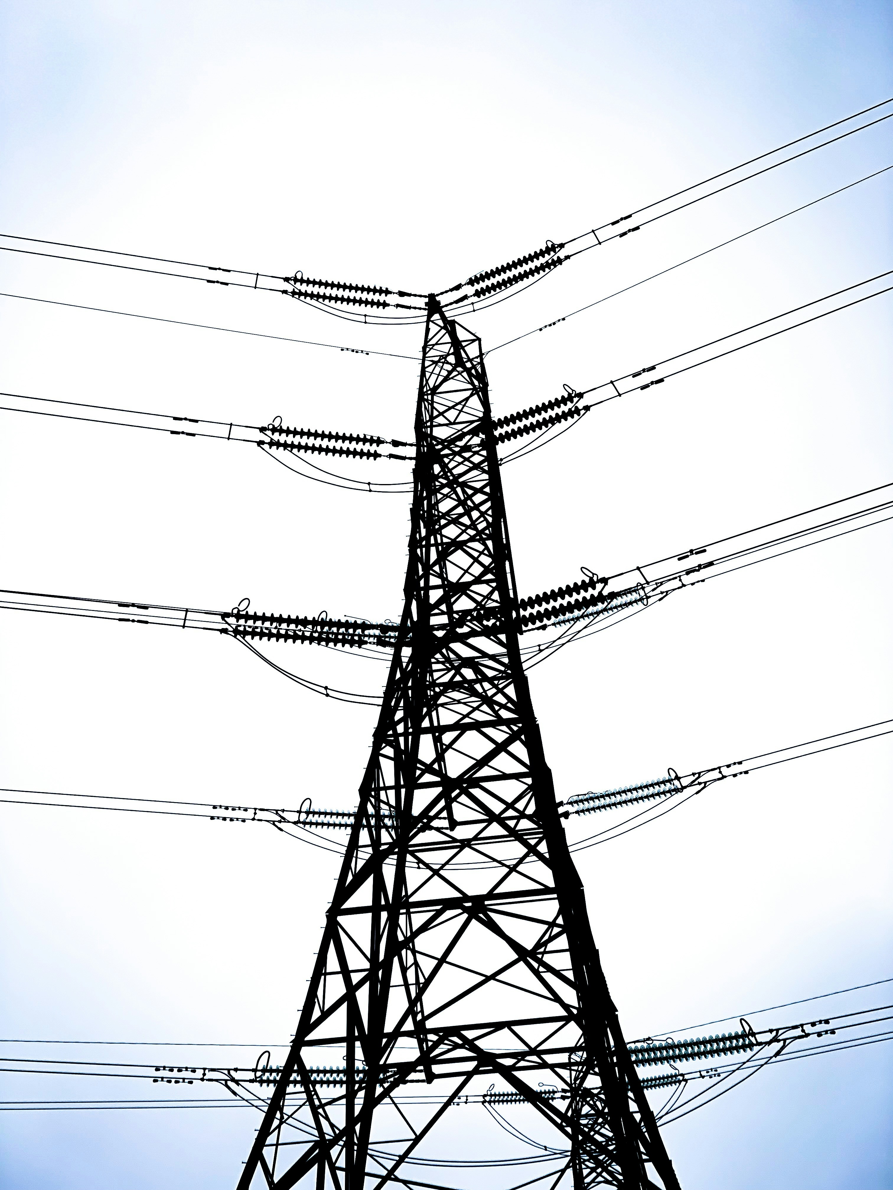 Skybound Lattice: Silhouette of a Transmission Tower Against a Blown-Out Sky