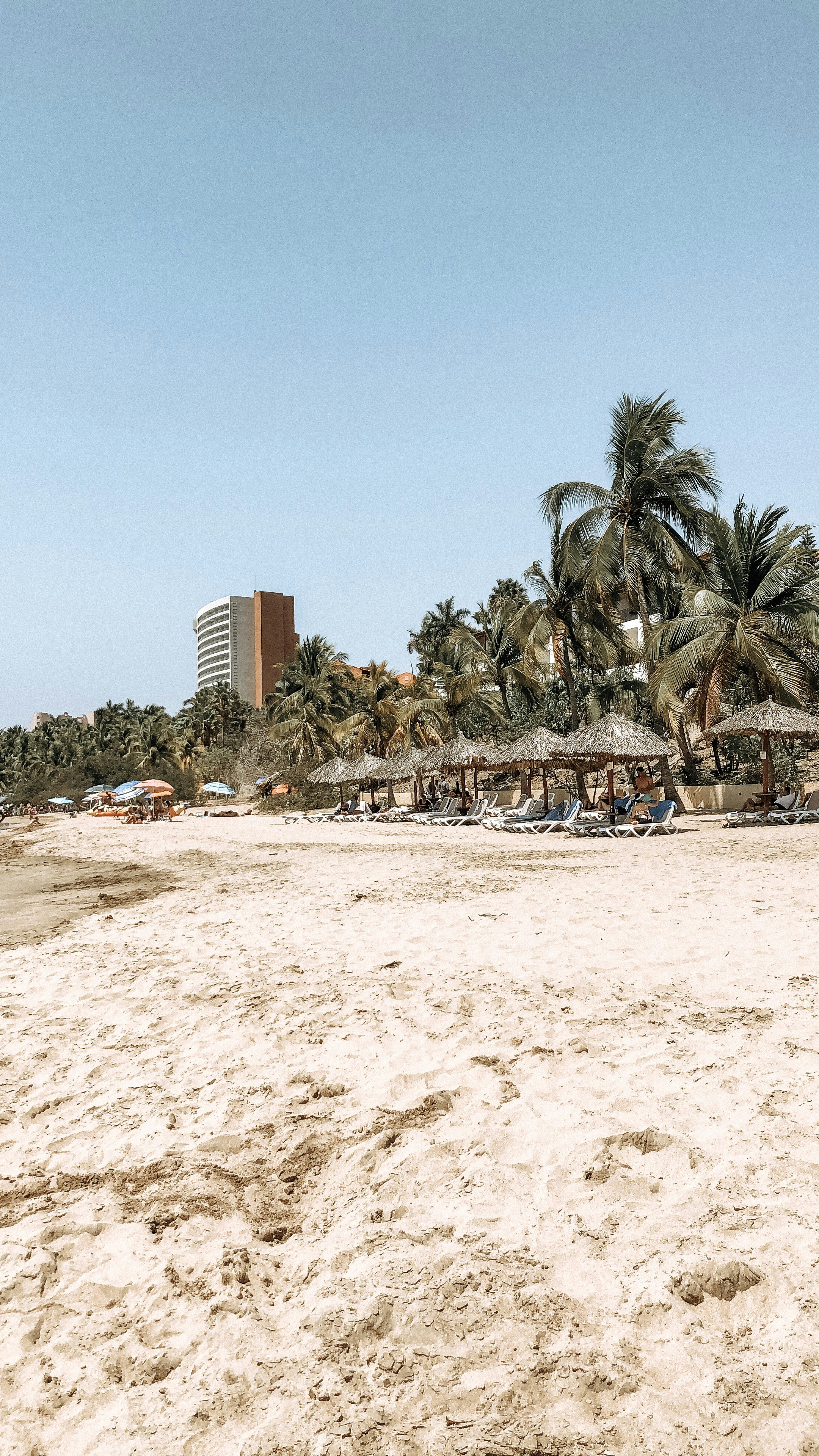 Palm-Dotted Beachfront with Sunset-Glow Hotel Silhouette