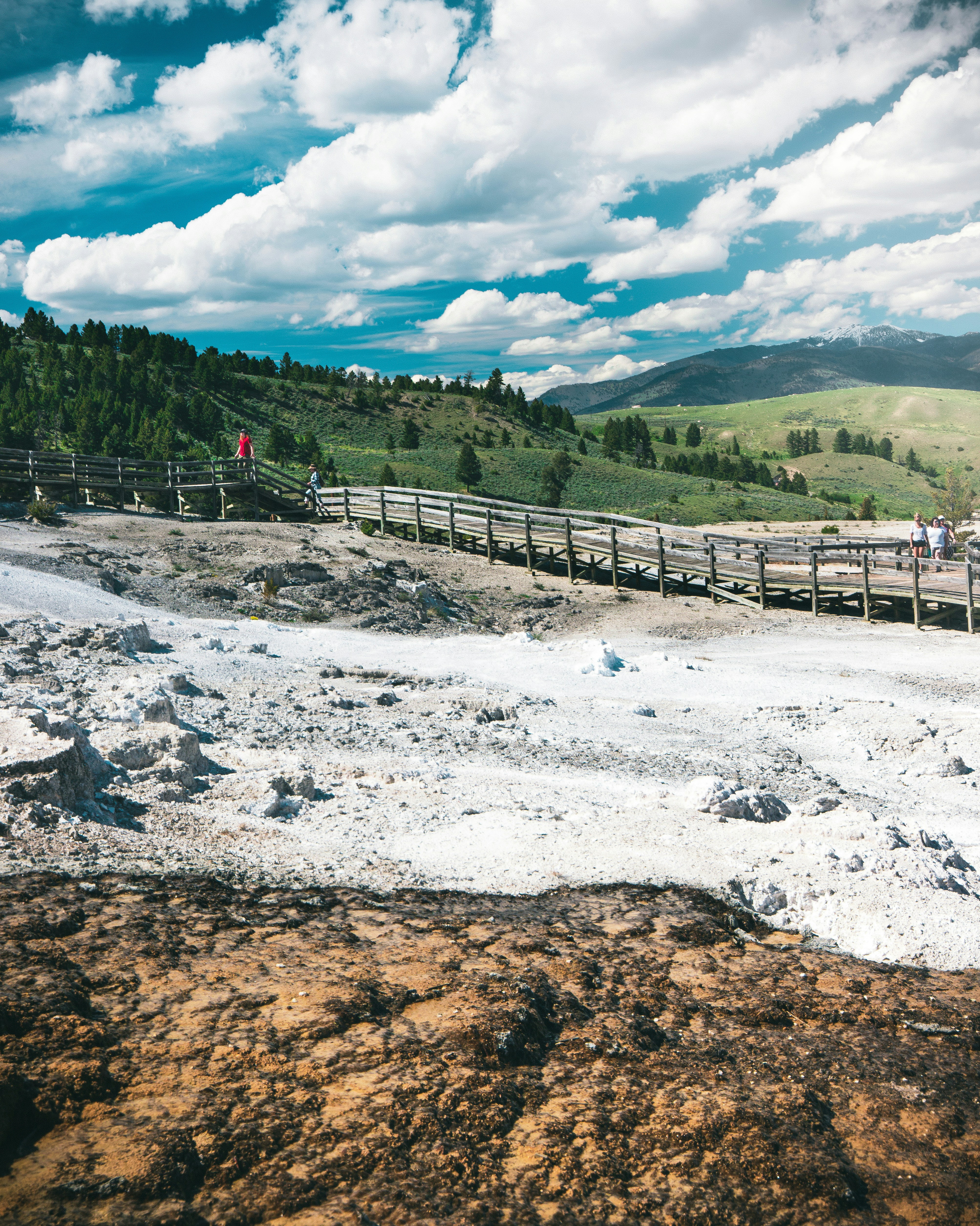 Crimson Hiker on a Geothermal Boardwalk Under a Cloud-Kissed Sky