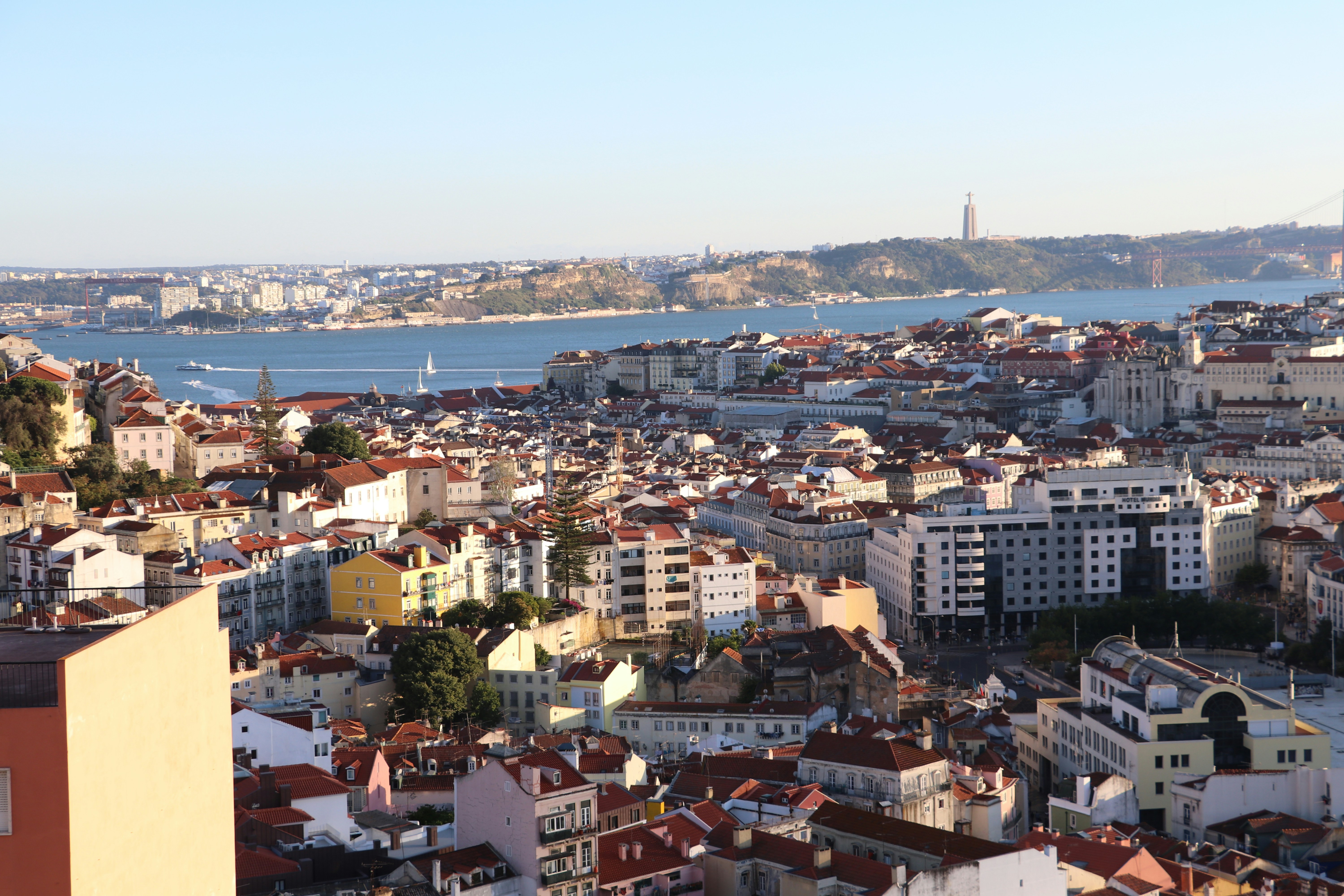 Panoramic view of Lisbon's colorful rooftops and the Tagus River, showcasing the city's architectural diversity and vibrant atmosphere.