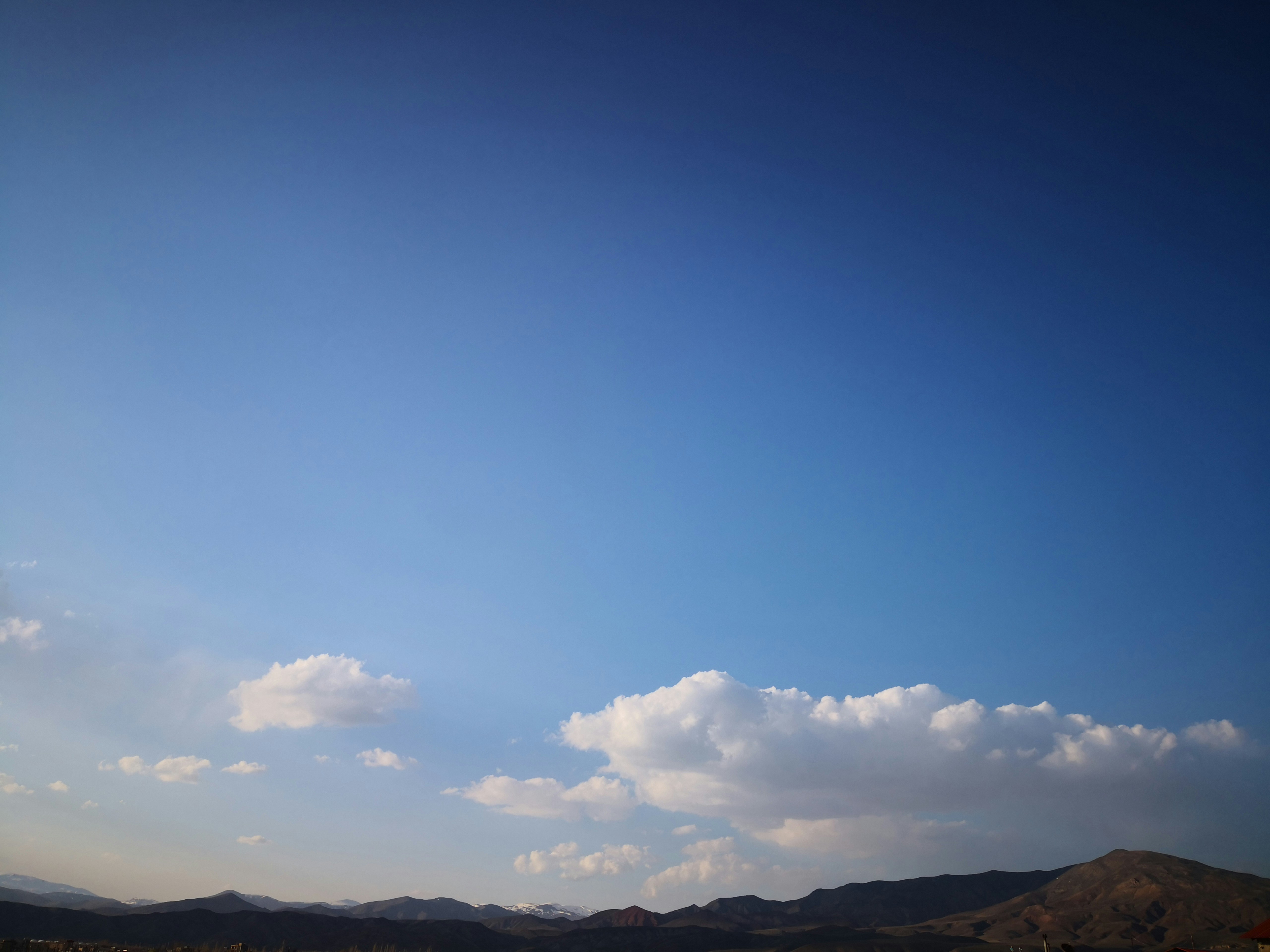 Expansive sky transitioning from deep blue to soft clouds above distant mountains, capturing a serene moment in nature.