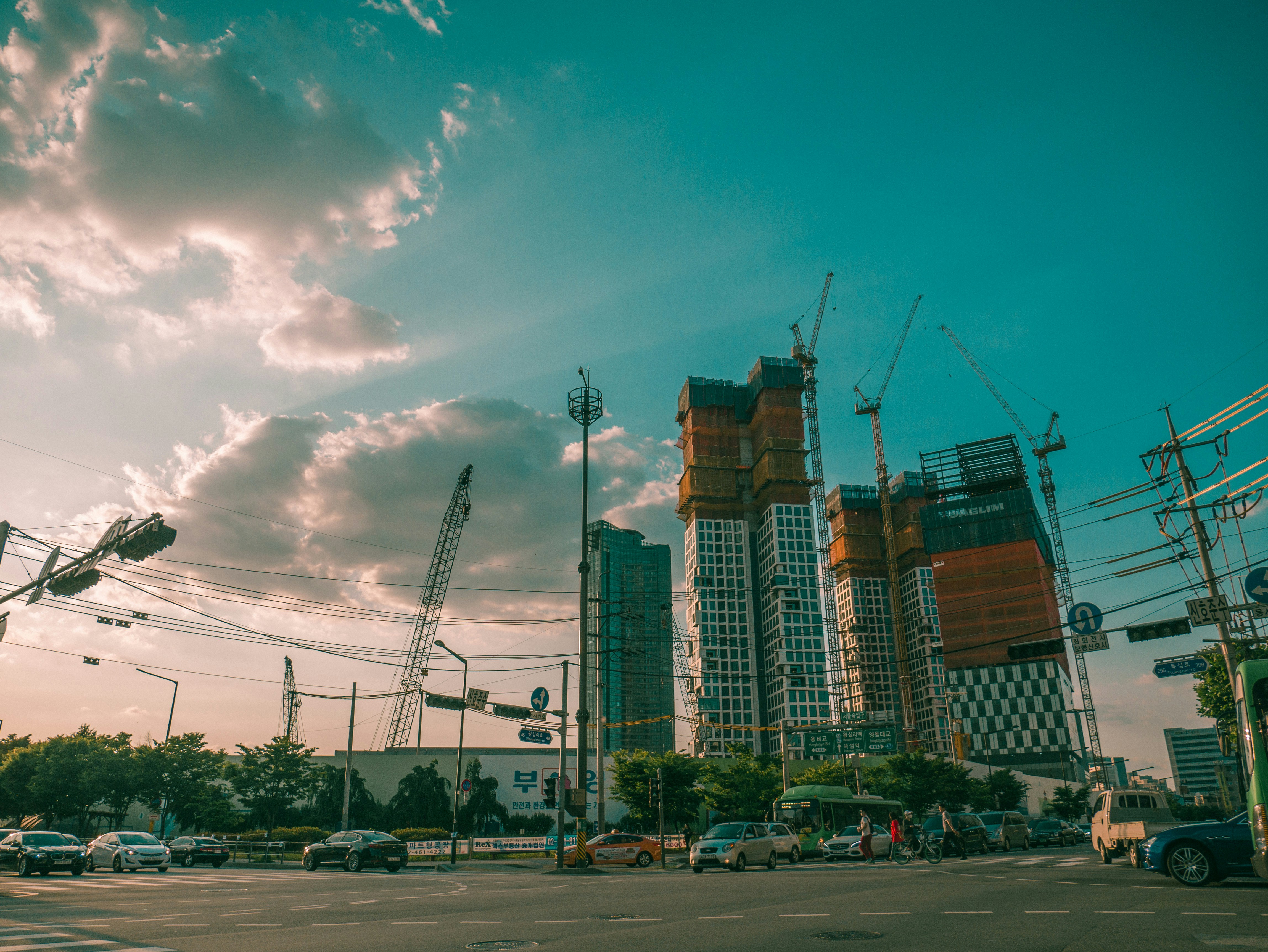 Rising Skyline: Construction Cranes Reframe a Busy City Intersection at Dusk