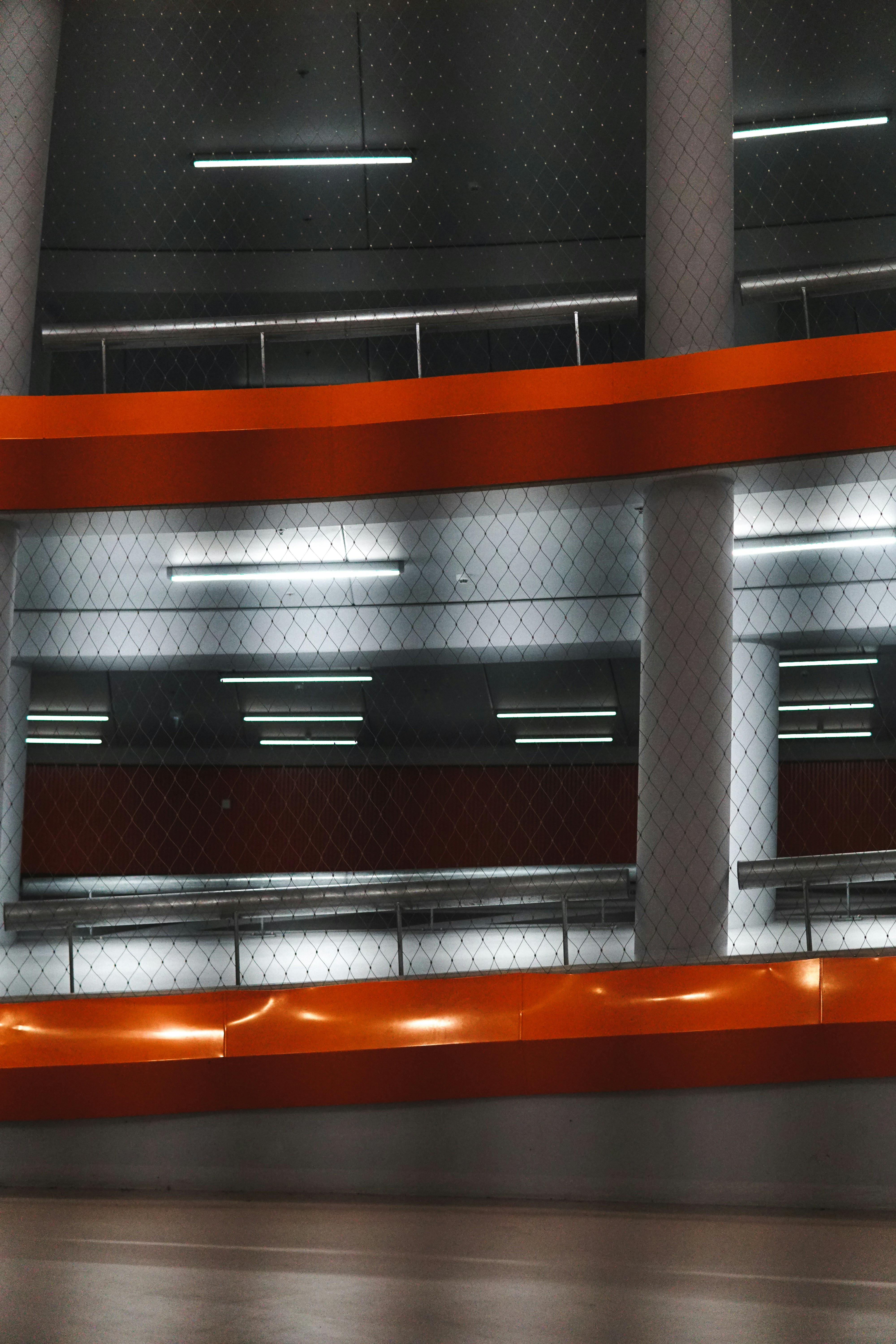 Abstract architectural interior featuring curved orange elements against a backdrop of sleek metallic surfaces and soft lighting.