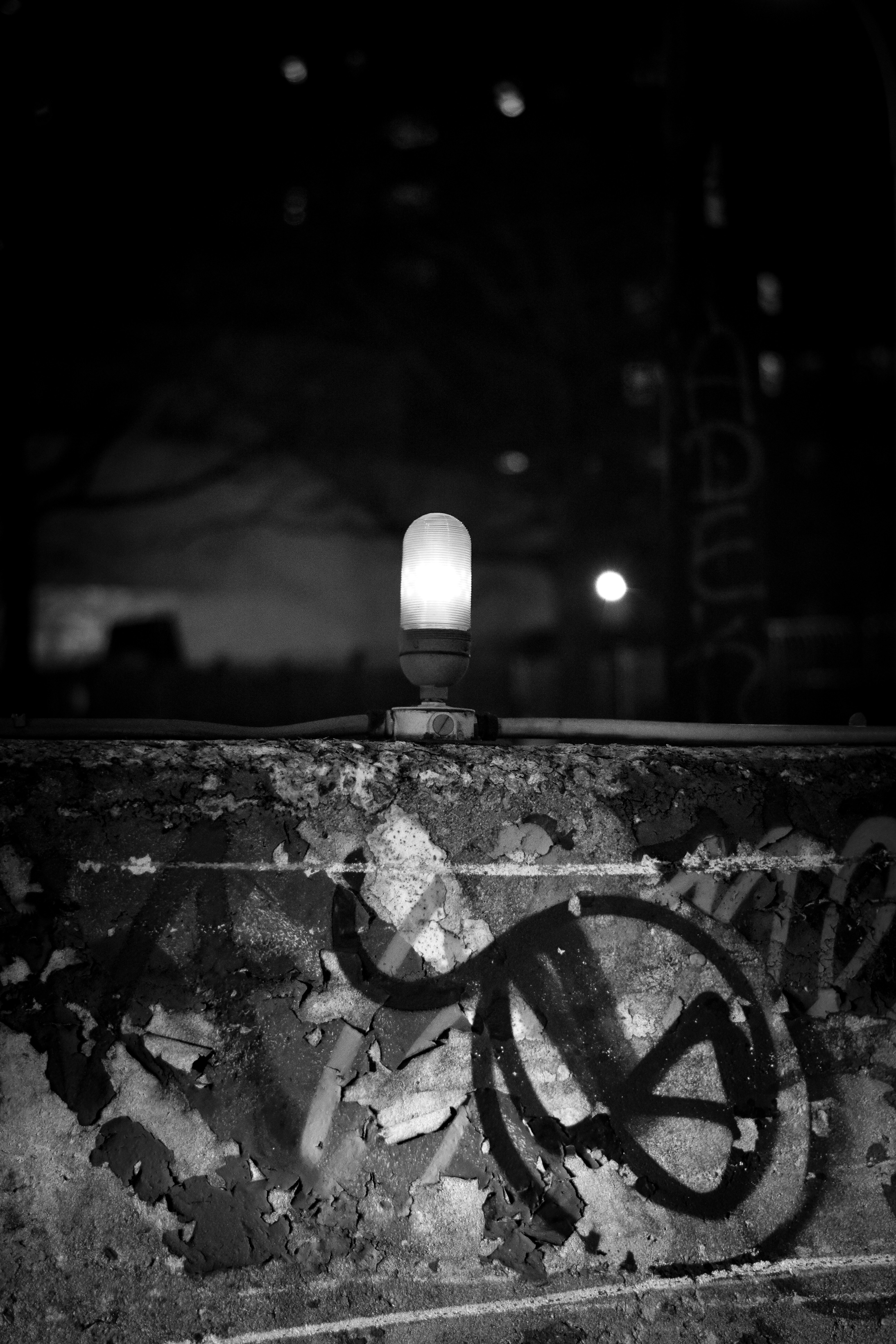 Lone Beacon Over a Graffiti-Streaked Ledge at Night