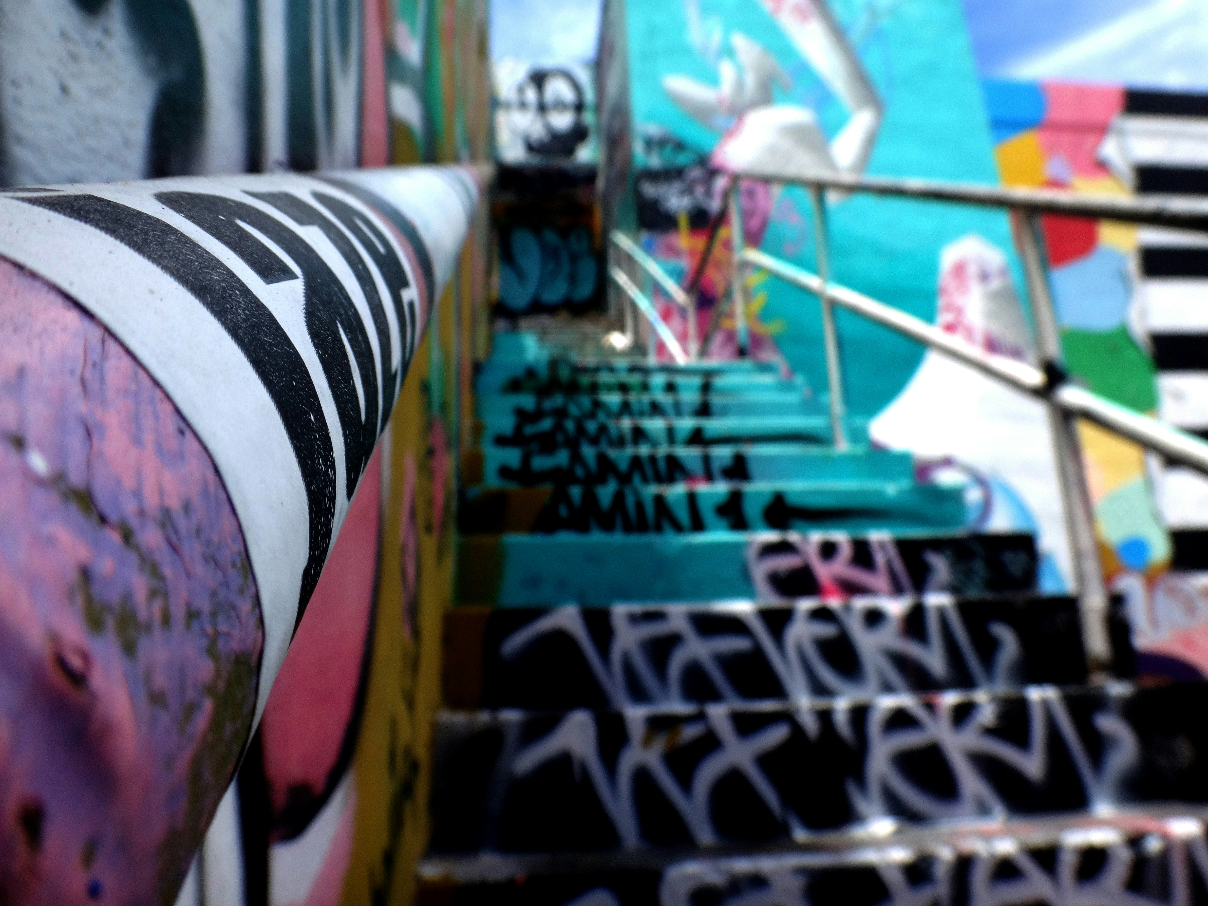 Vibrant stairway adorned with graffiti, leading upwards amidst a backdrop of colorful murals. The scene captures the essence of urban artistry.