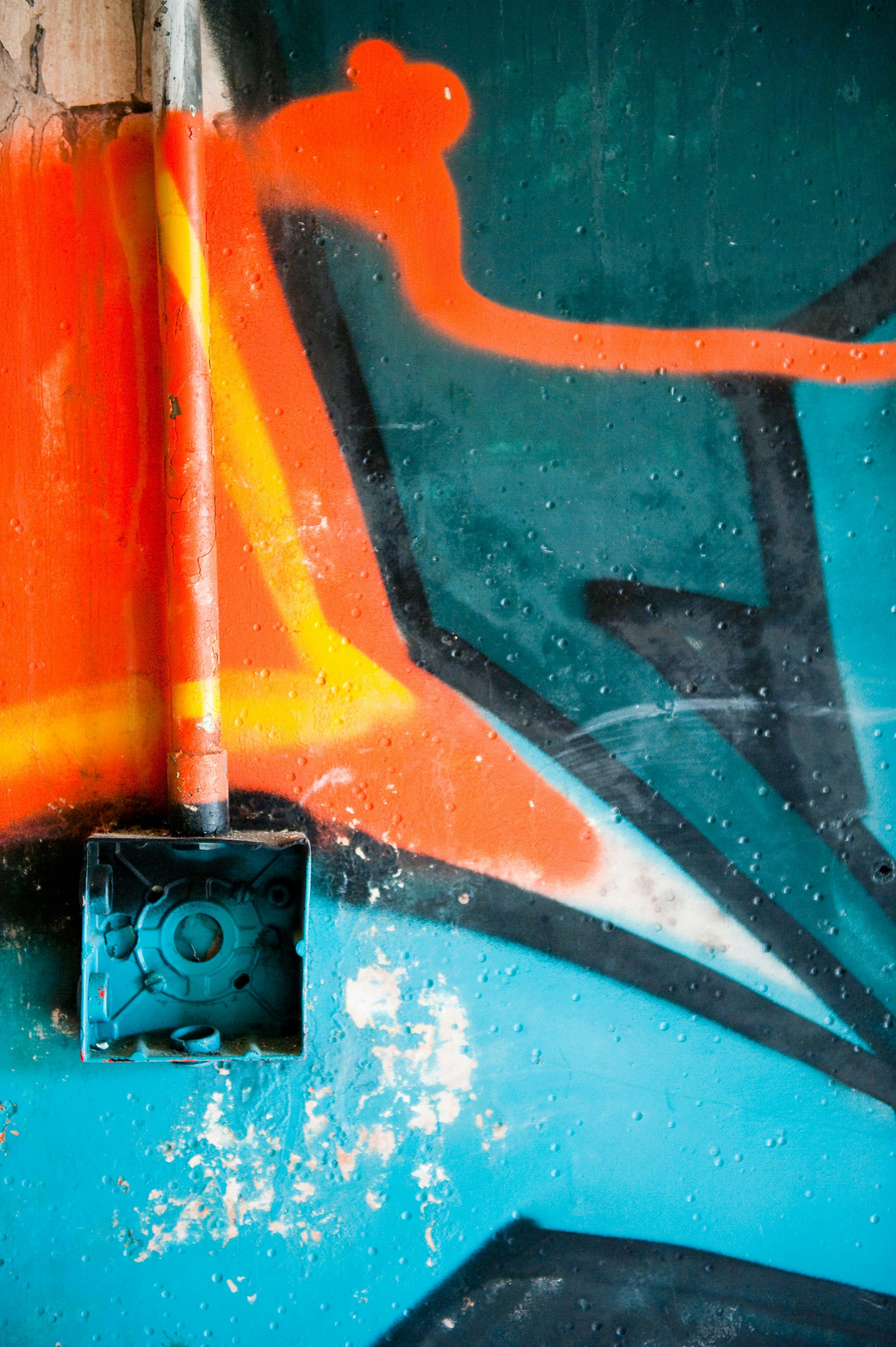 Vibrant graffiti with bold colors and a contrasting blue electrical box against a textured wall.
