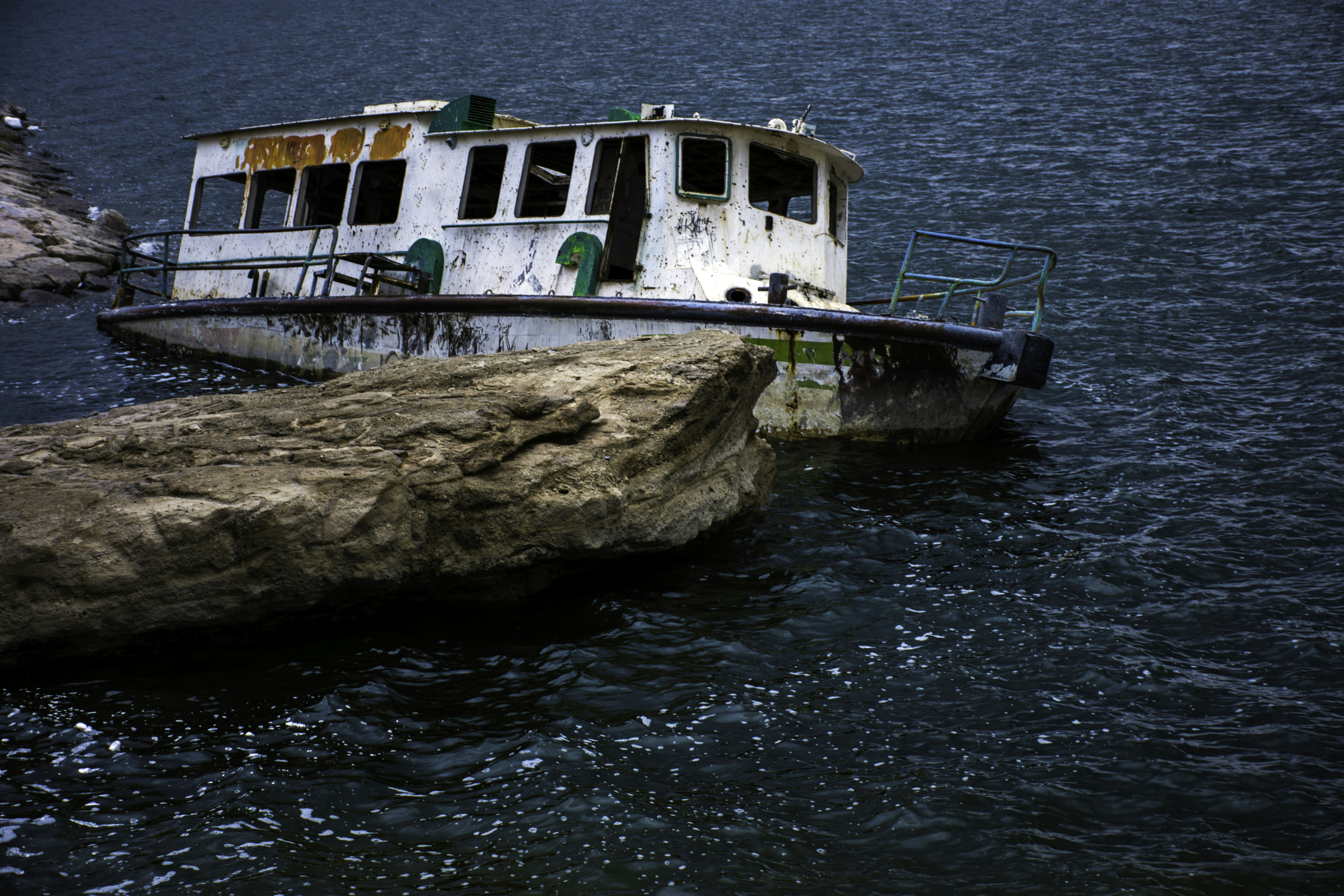 Weathered Cabin Boat Adrift by a Rugged Rock in a Turquoise Sea