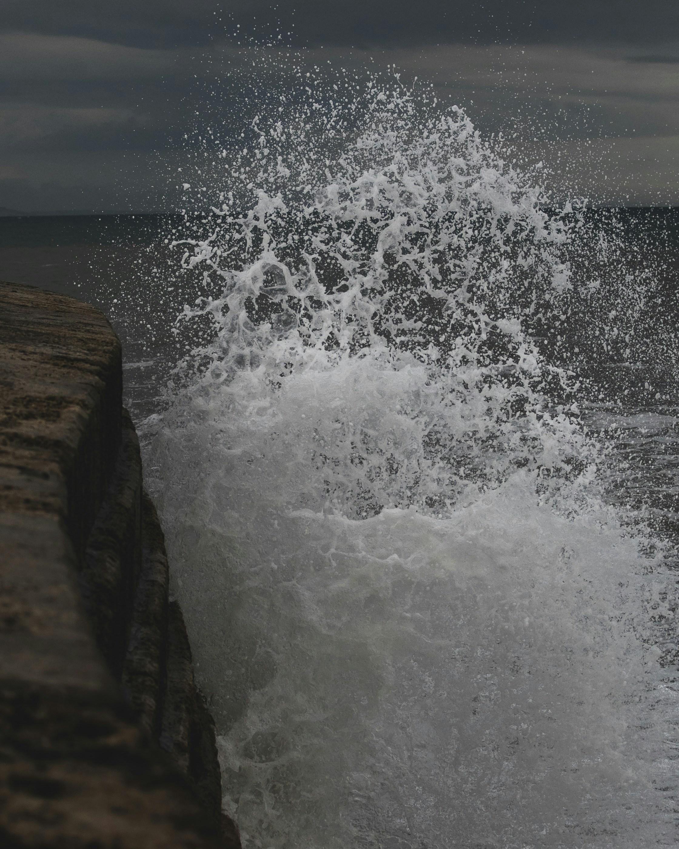 Powerful waves crashing against a rocky shore under a moody sky.