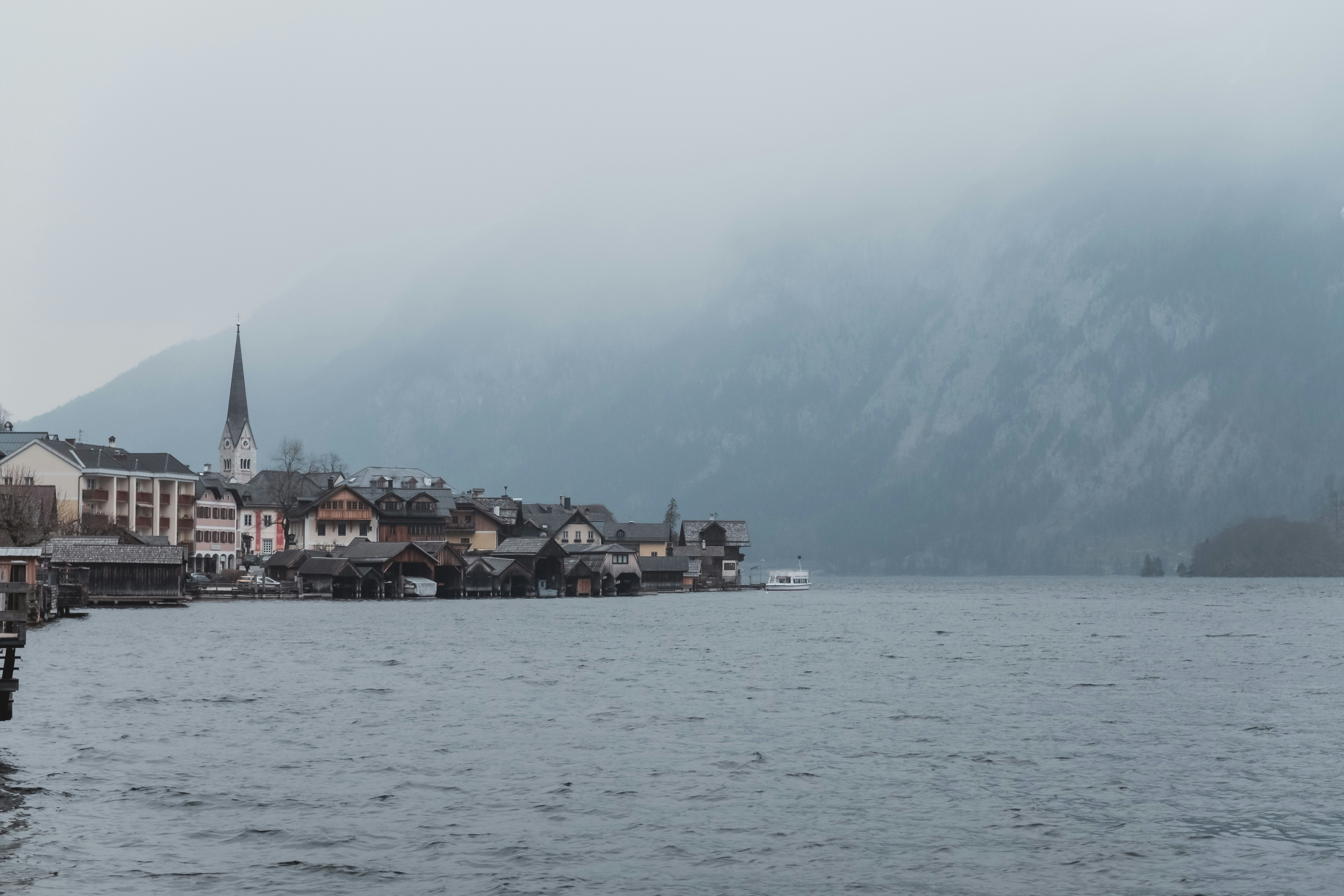 Fog envelops the quaint lakeside town of Hallstatt, with distant mountains shrouded in mist.