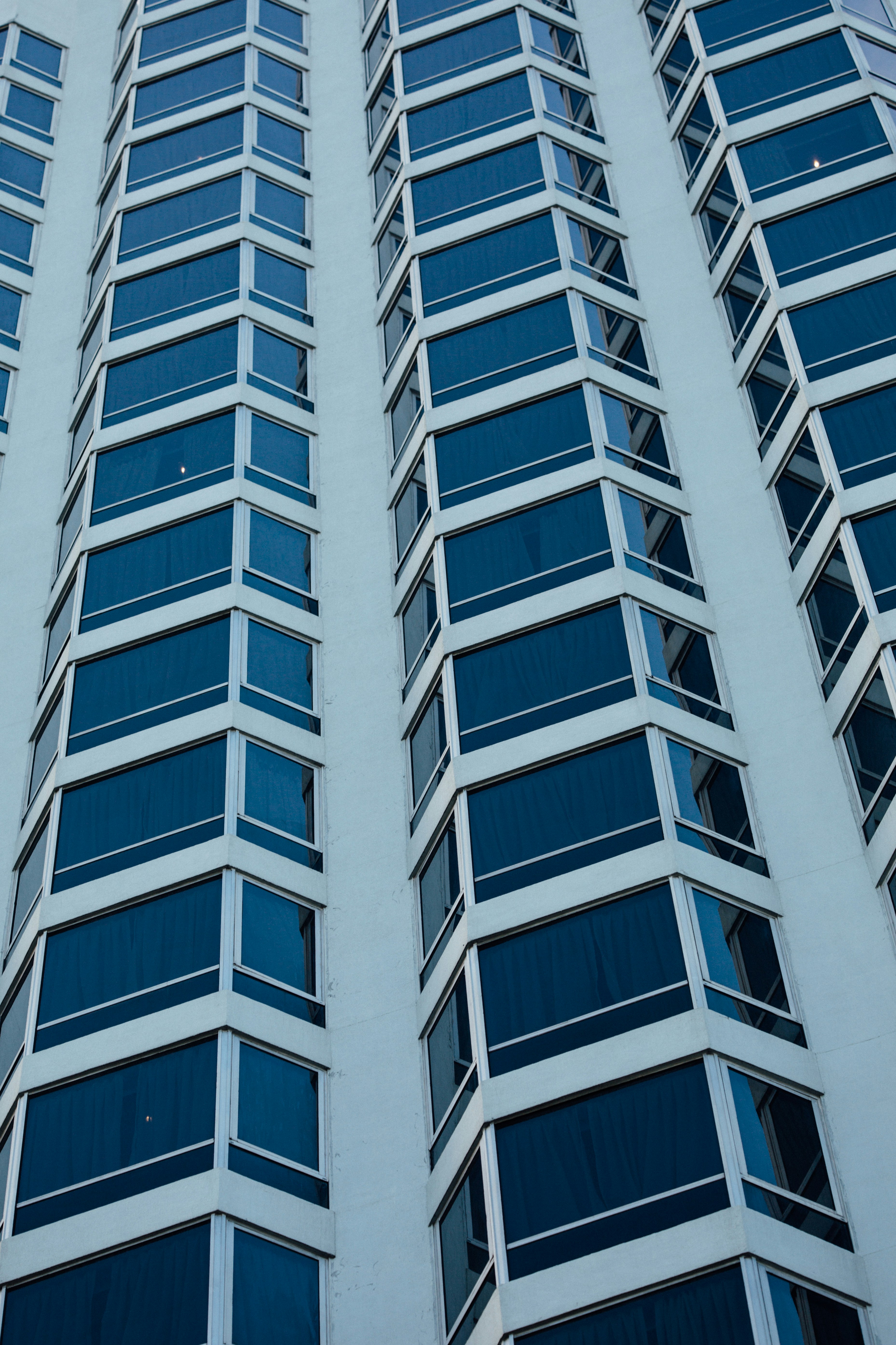 Geometric arrangement of windows on a modern high-rise building, showcasing reflections and structural design.