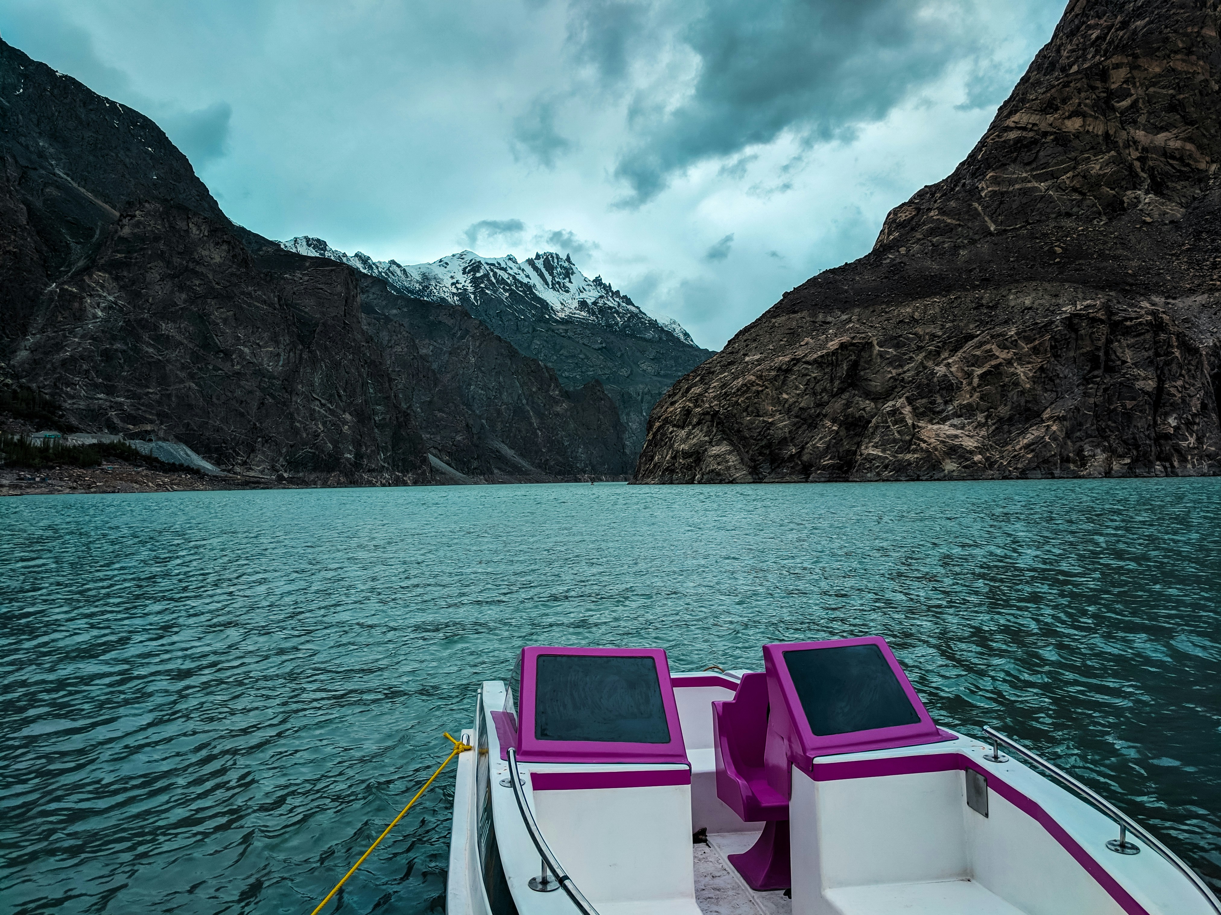 Magenta-Trim Boat Amid Teal Fjord Between Shadowed Peaks