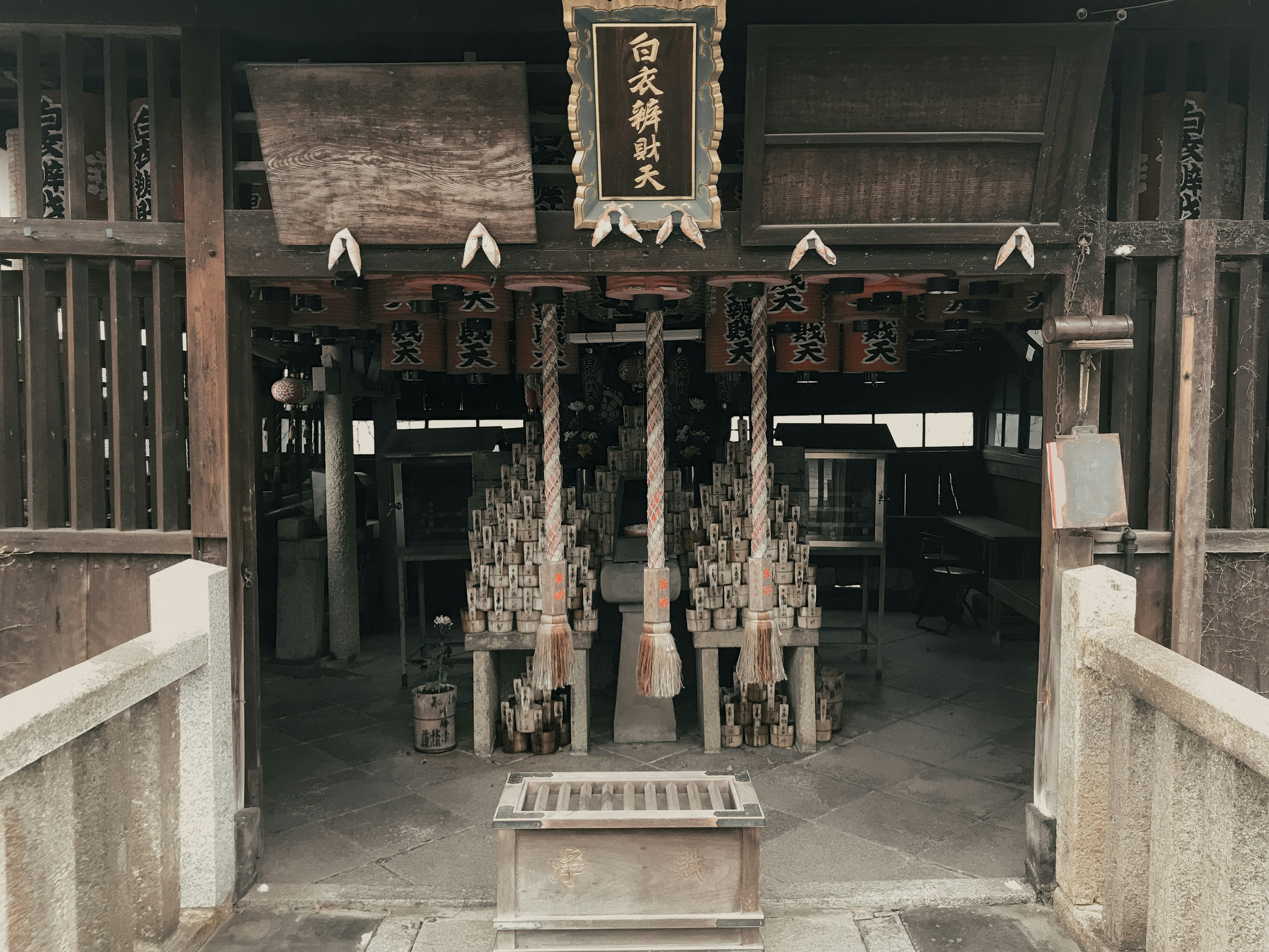 Traditional wooden shrine entrance adorned with lanterns and prayer ropes.