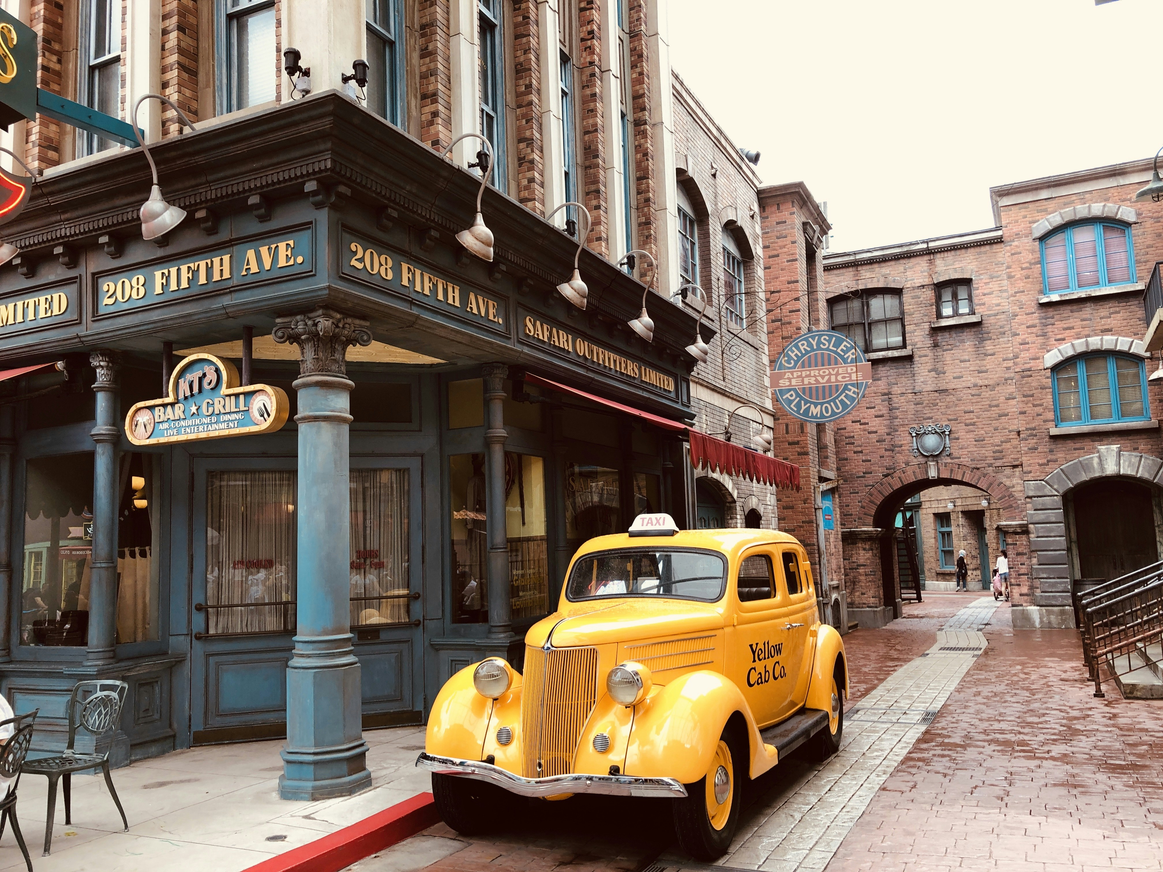 Classic yellow taxi cab parked beside the road near building during day ...