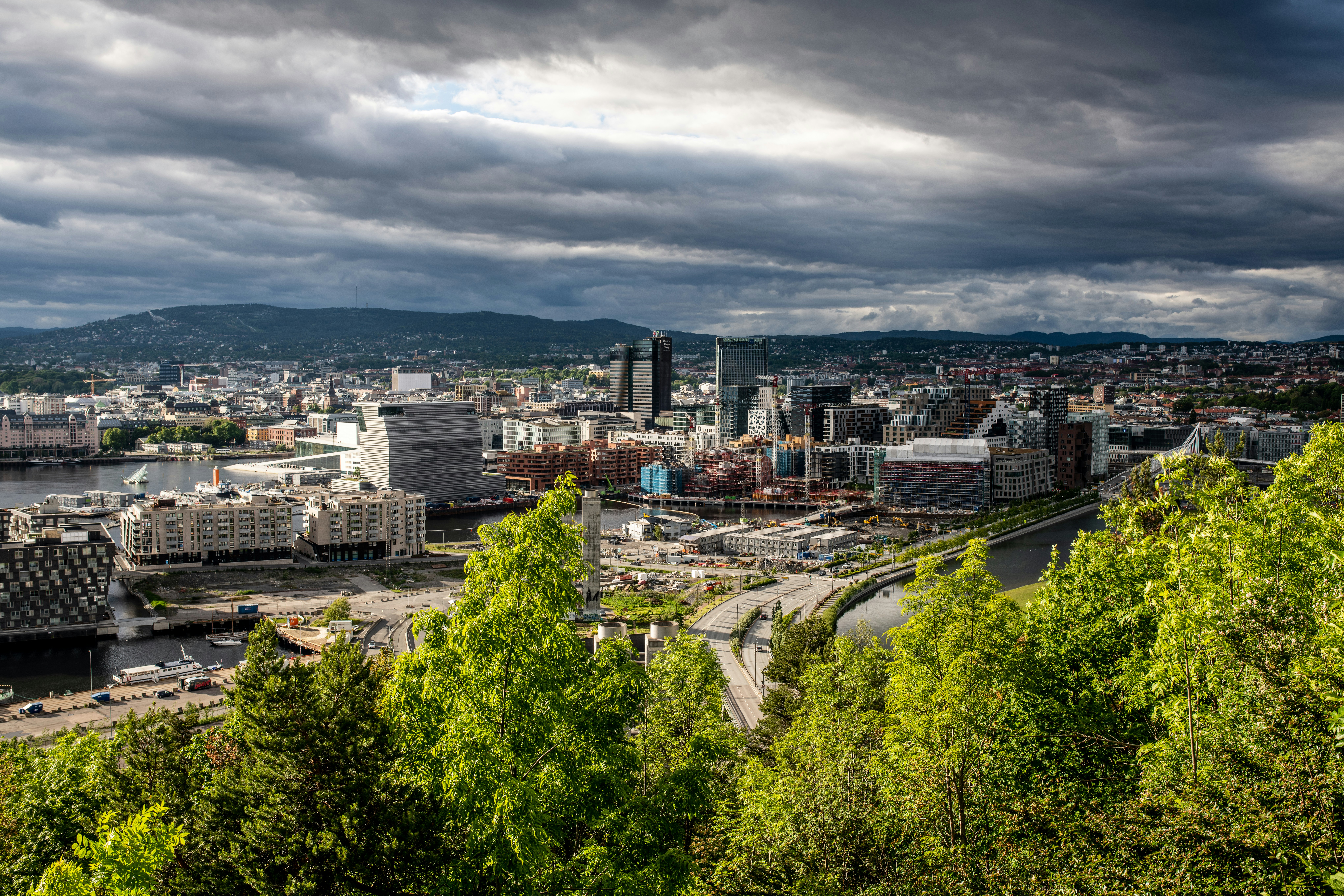Verdant Edge: Cityscape Framed by Hills and Storm Clouds