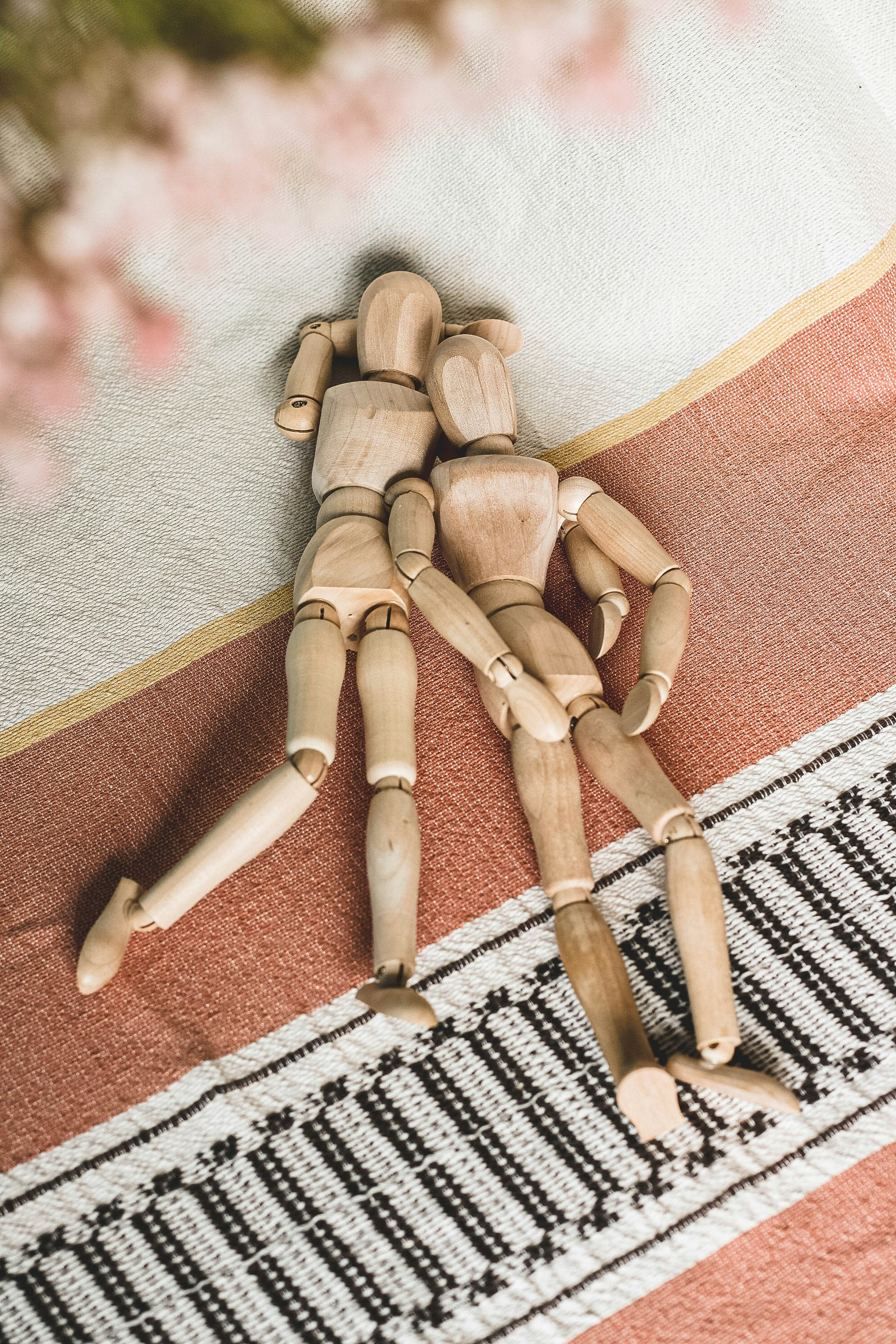 Wooden Articulated Figure Resting on Colorful Rug Strips