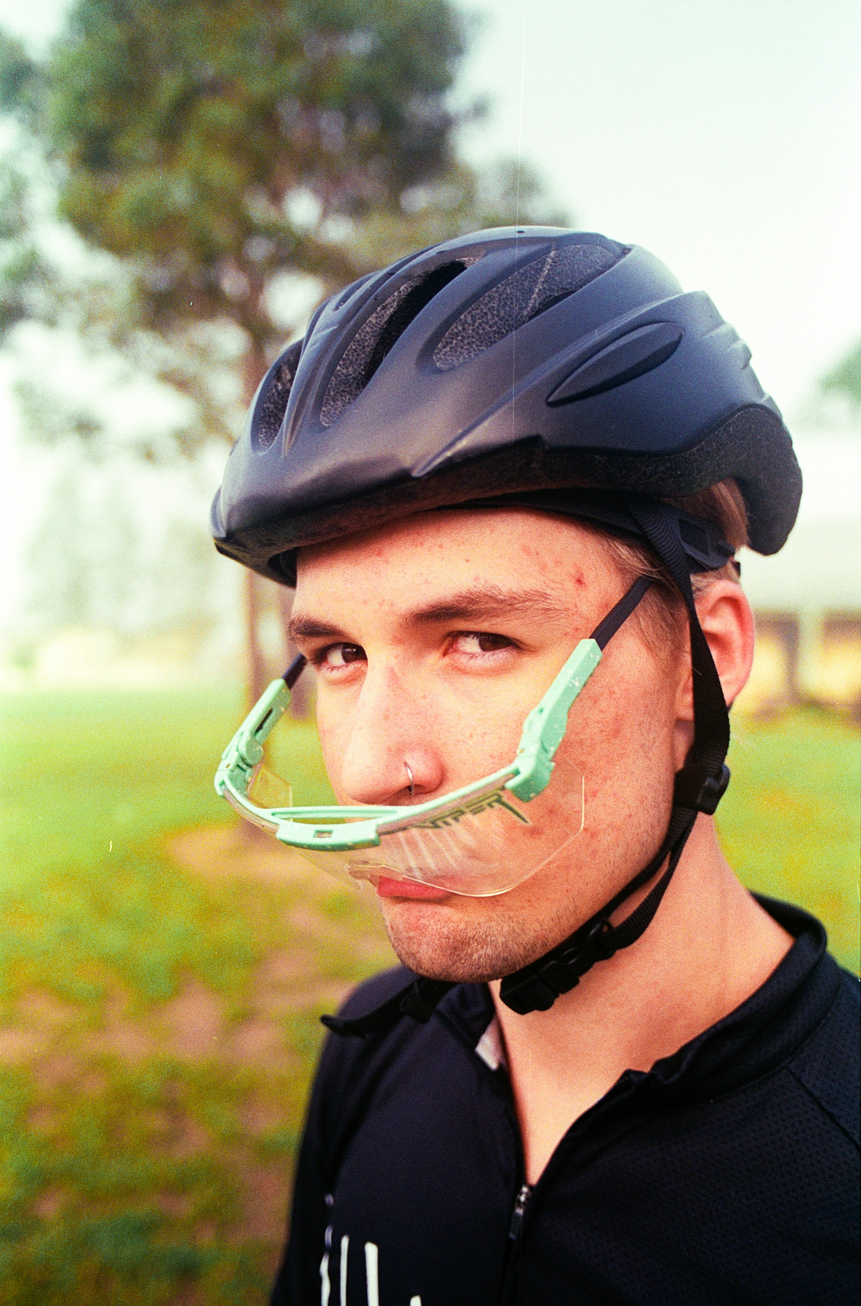 Gaze Under the Shield: Close Portrait of a Cyclist in a Green Park
