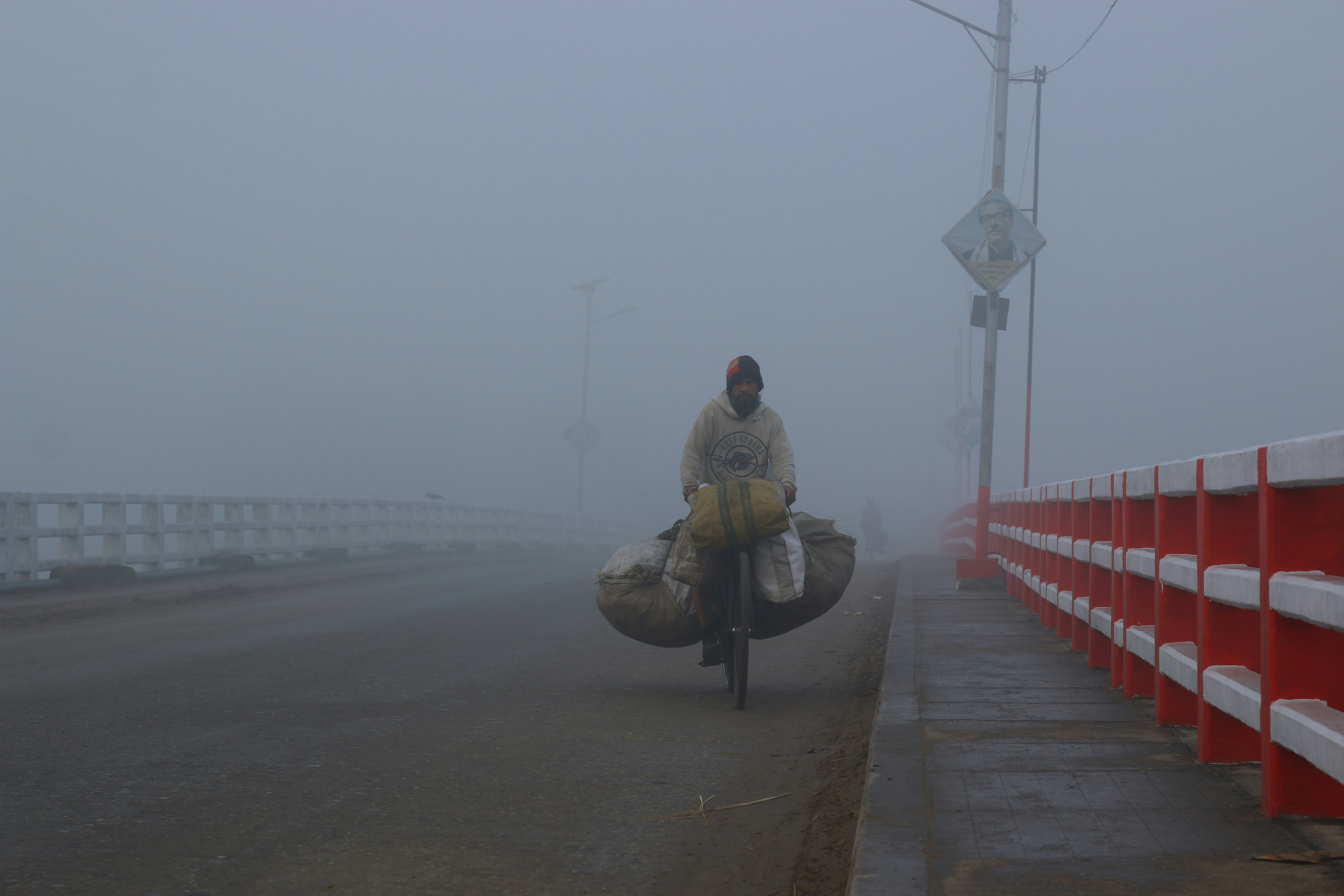 Lone Cyclist Traversing a Misty Bridge