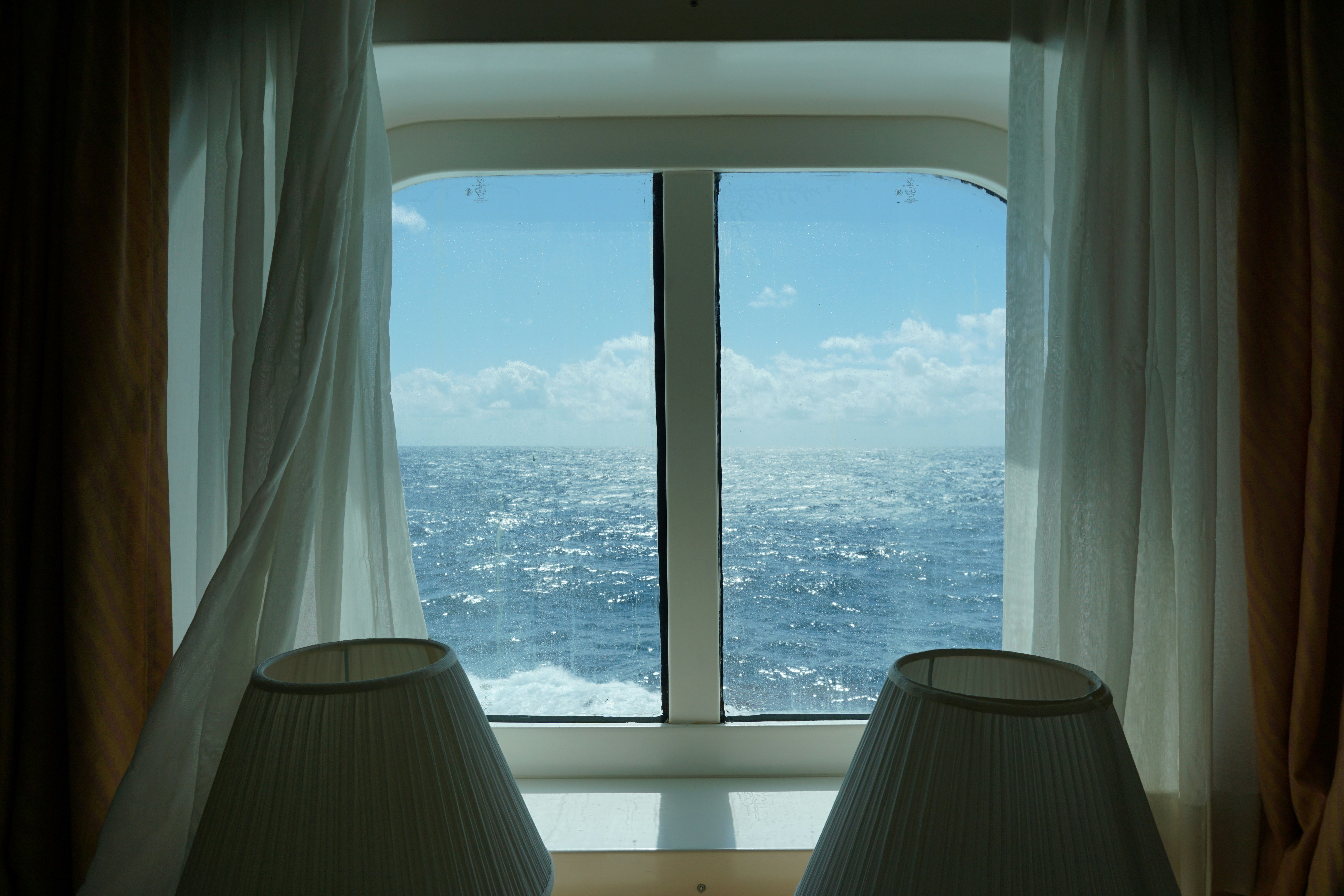 Horizon Through a Ship's Curtain: Ocean Light Framed by Lamps