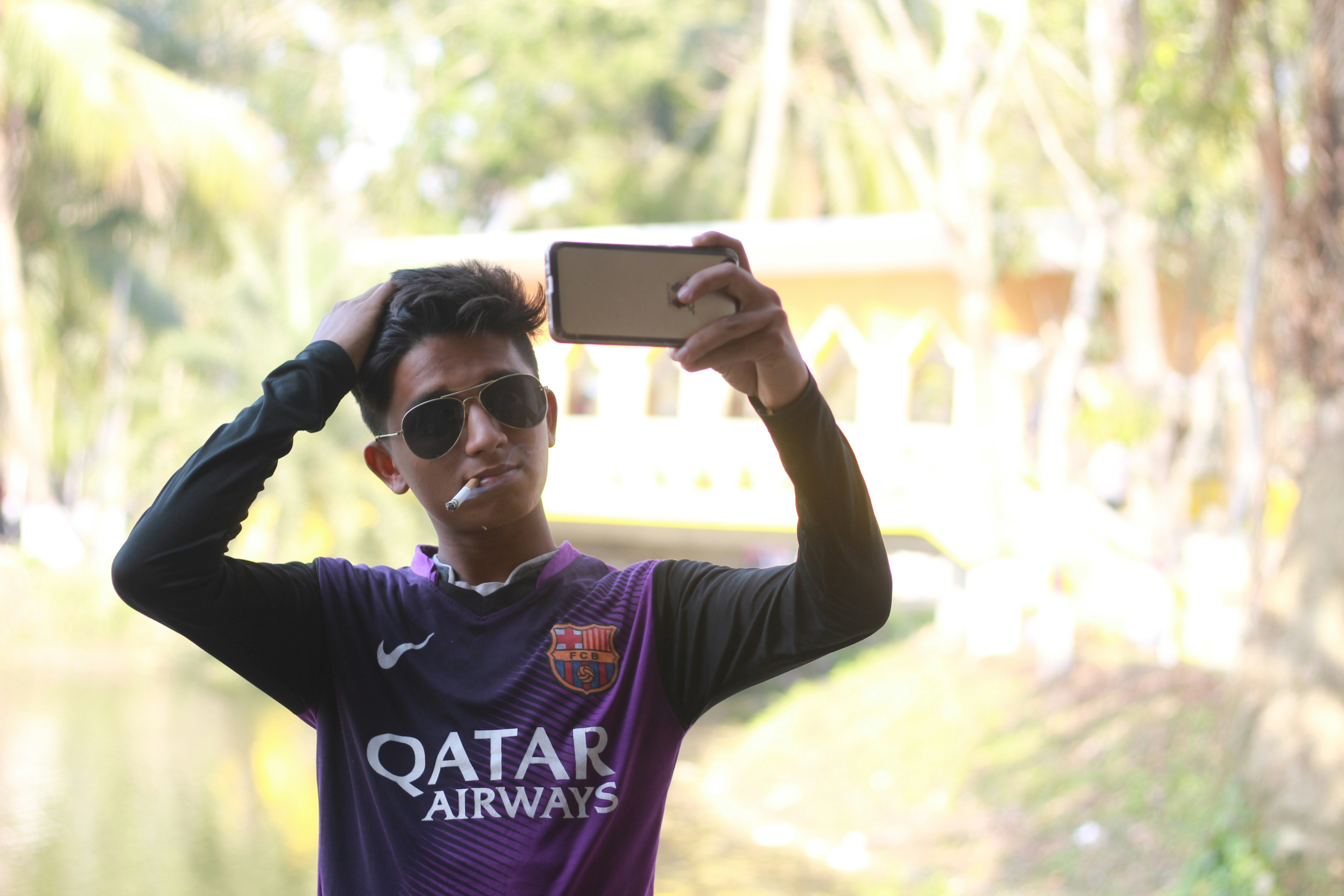 Selfie Under Blazing Backlight: Barça Fan Portrait Against a Blurred Tropical Backdrop