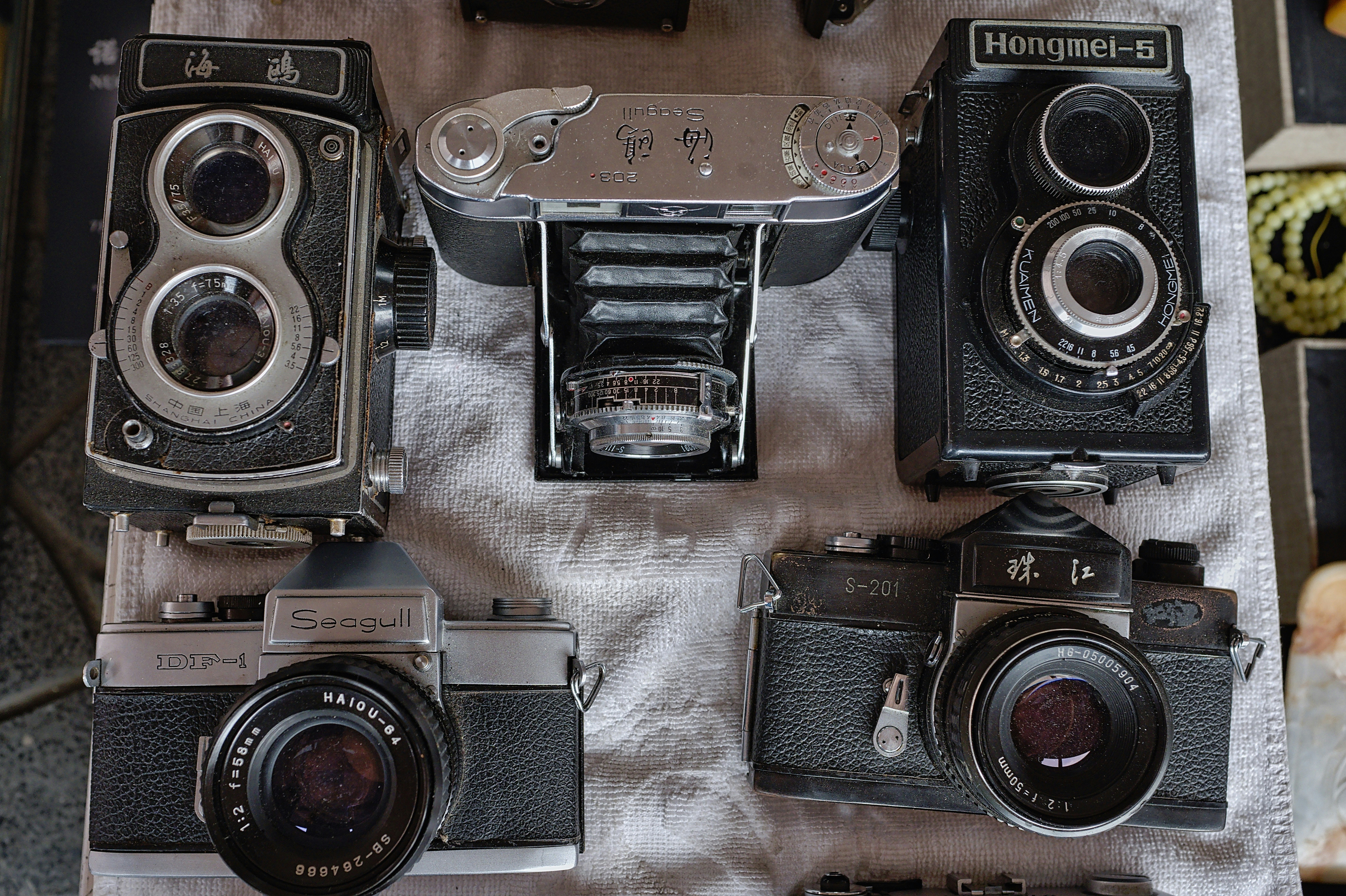 Vintage cameras arranged on soft fabric, showcasing diverse classic designs from different eras at an old market.