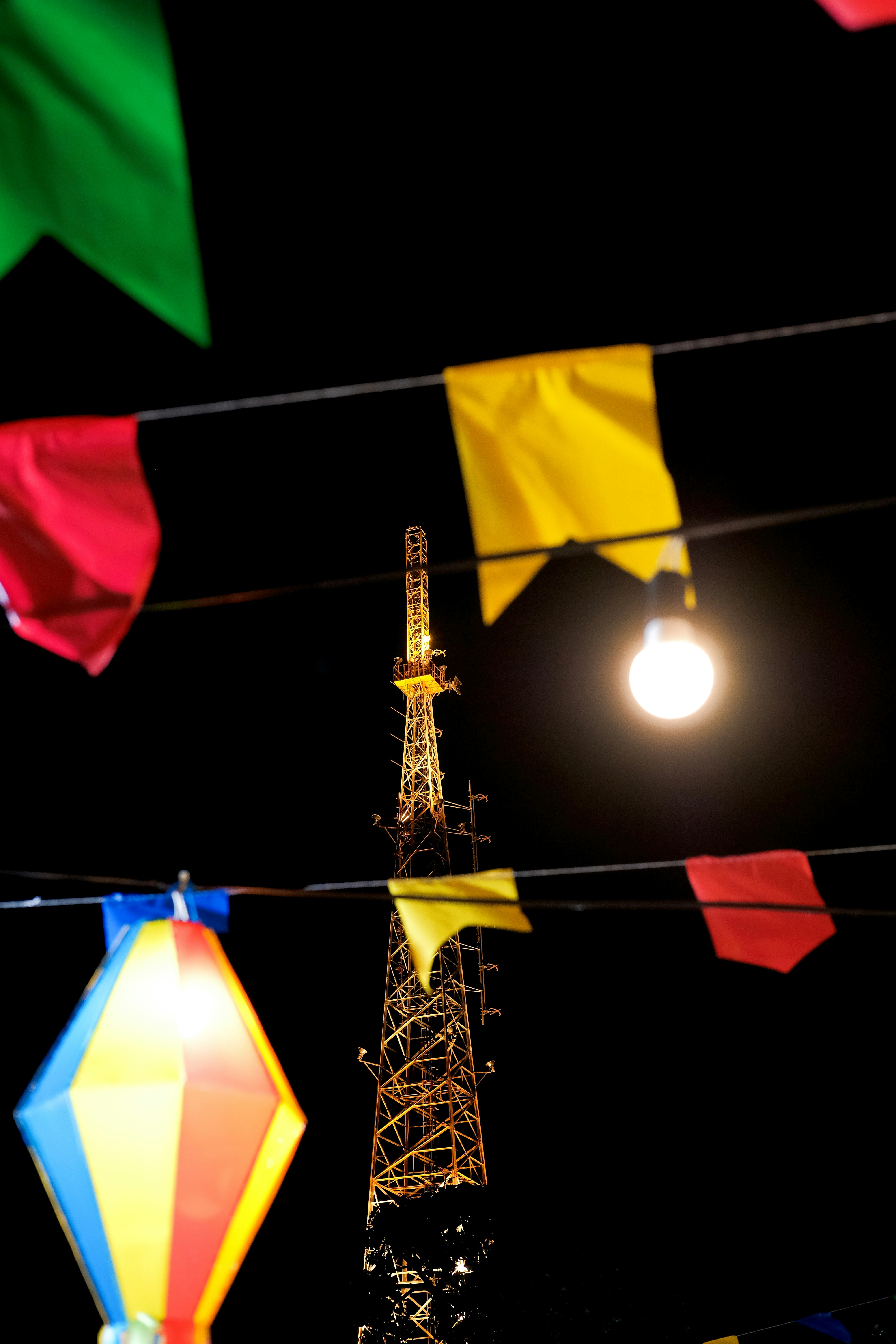 Midnight Chorus: A Lattice Tower Framed by Colorful Pennants