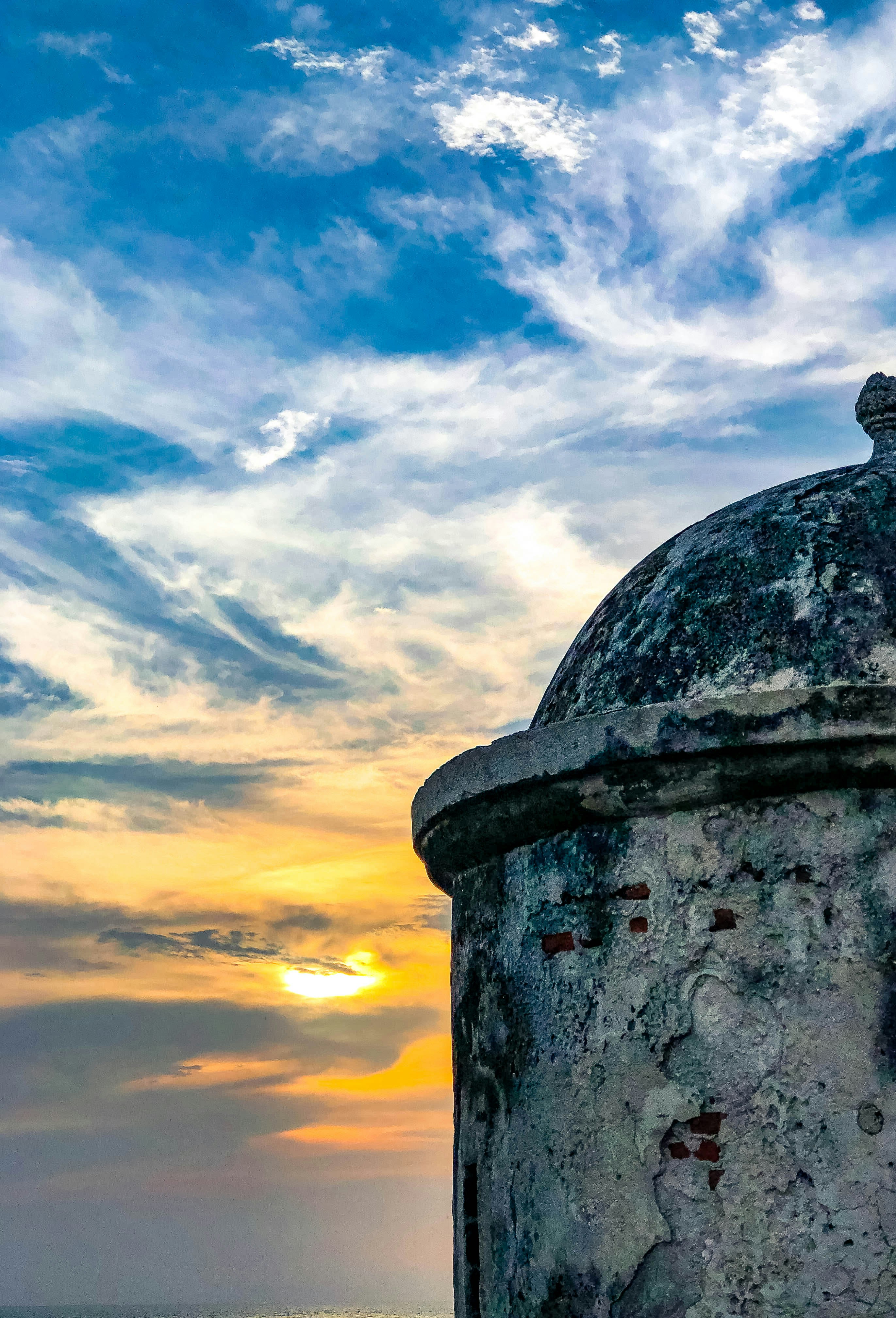 Ancient stone turret silhouetted against a vibrant sunset sky with swirling clouds.