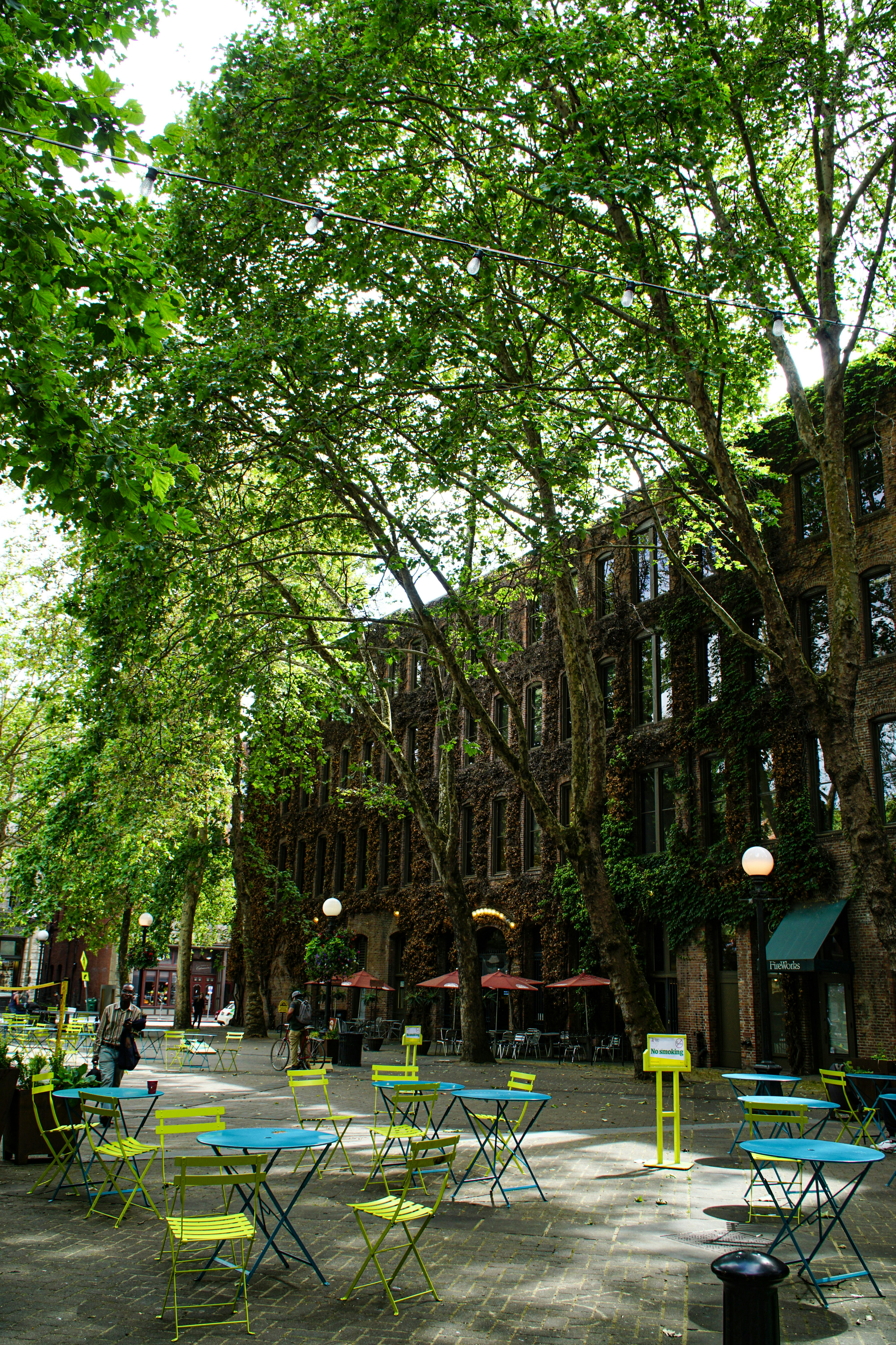 Charming outdoor seating area surrounded by lush trees and historic buildings, inviting relaxation and social interaction.