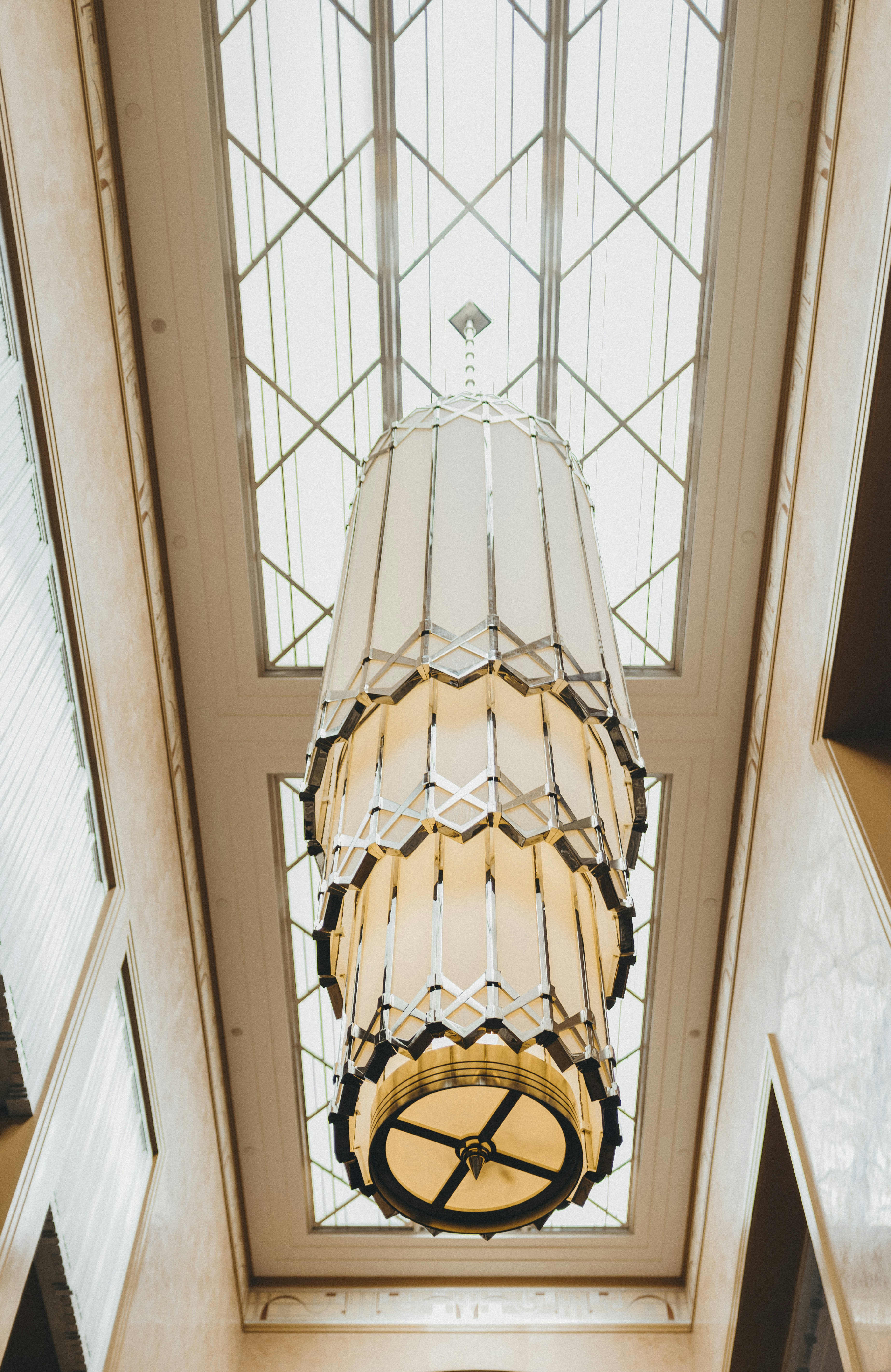 Elegant Art Deco chandelier suspended from a geometric ceiling, illuminating the space below with a warm glow.