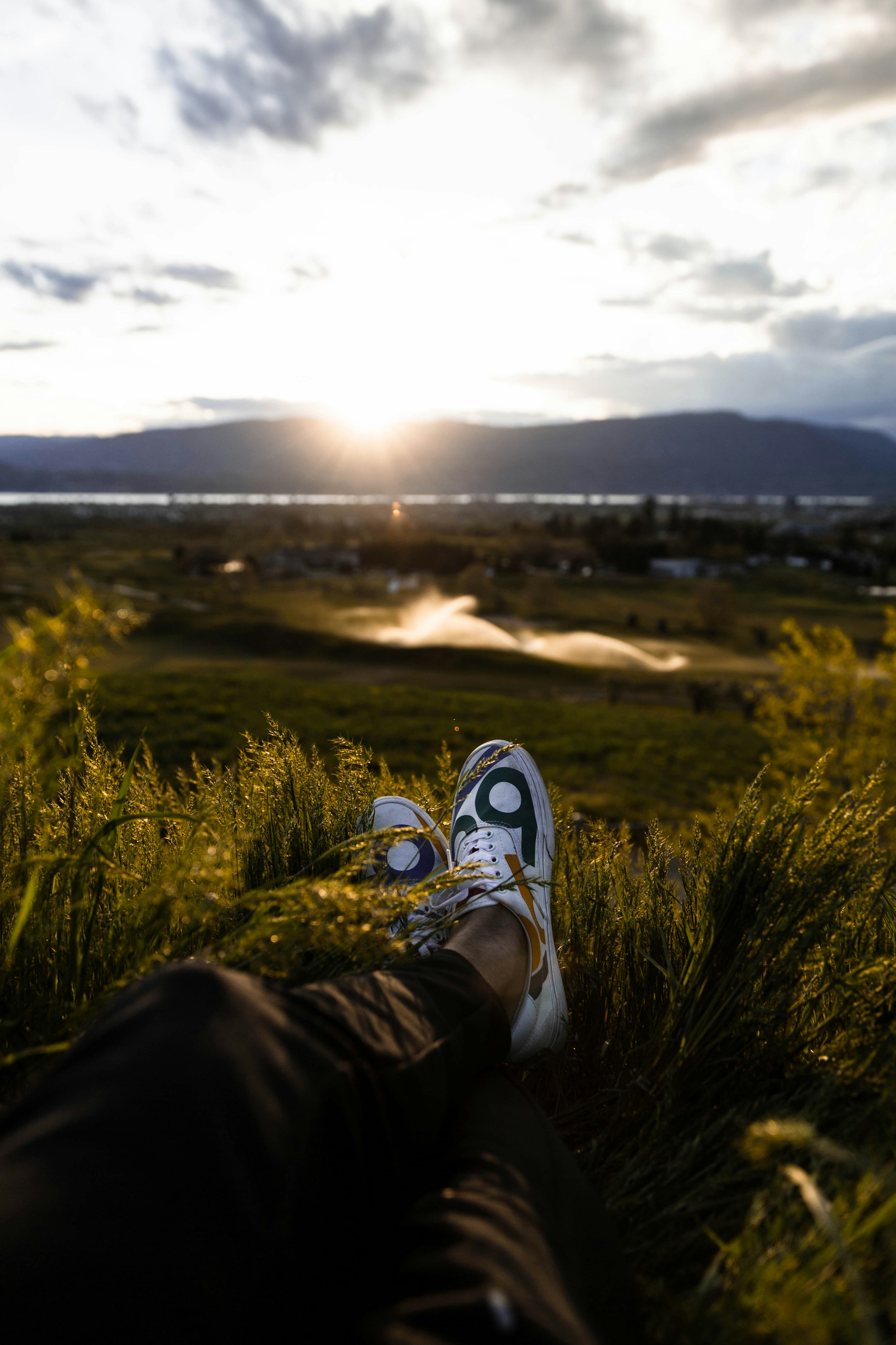 Sunset Over Grass: Quiet Contemplation with Sneakers Silhouetted