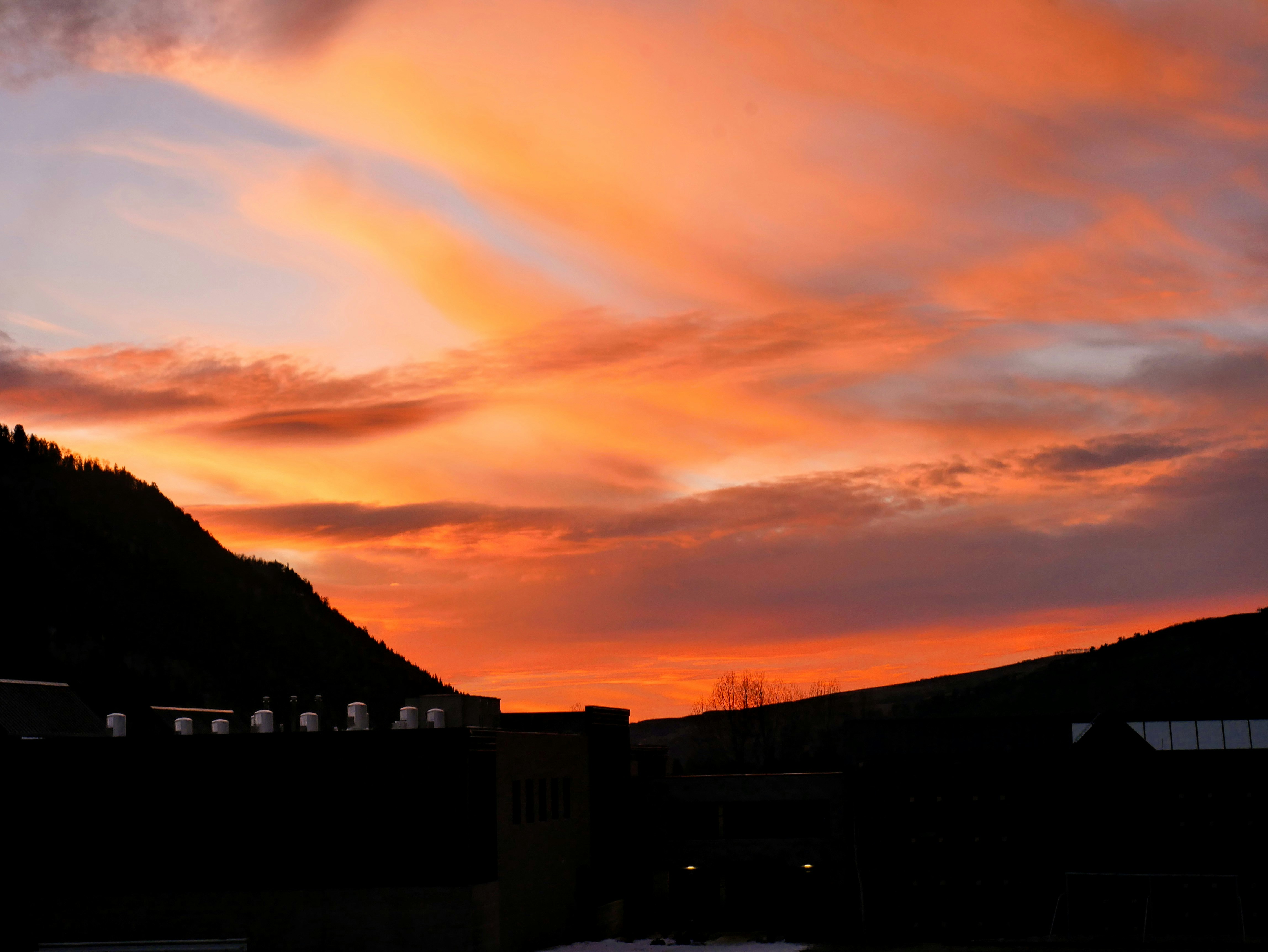 Embers at Dusk: Sunset Casts an Orange Veil Over Hills and Rooftops