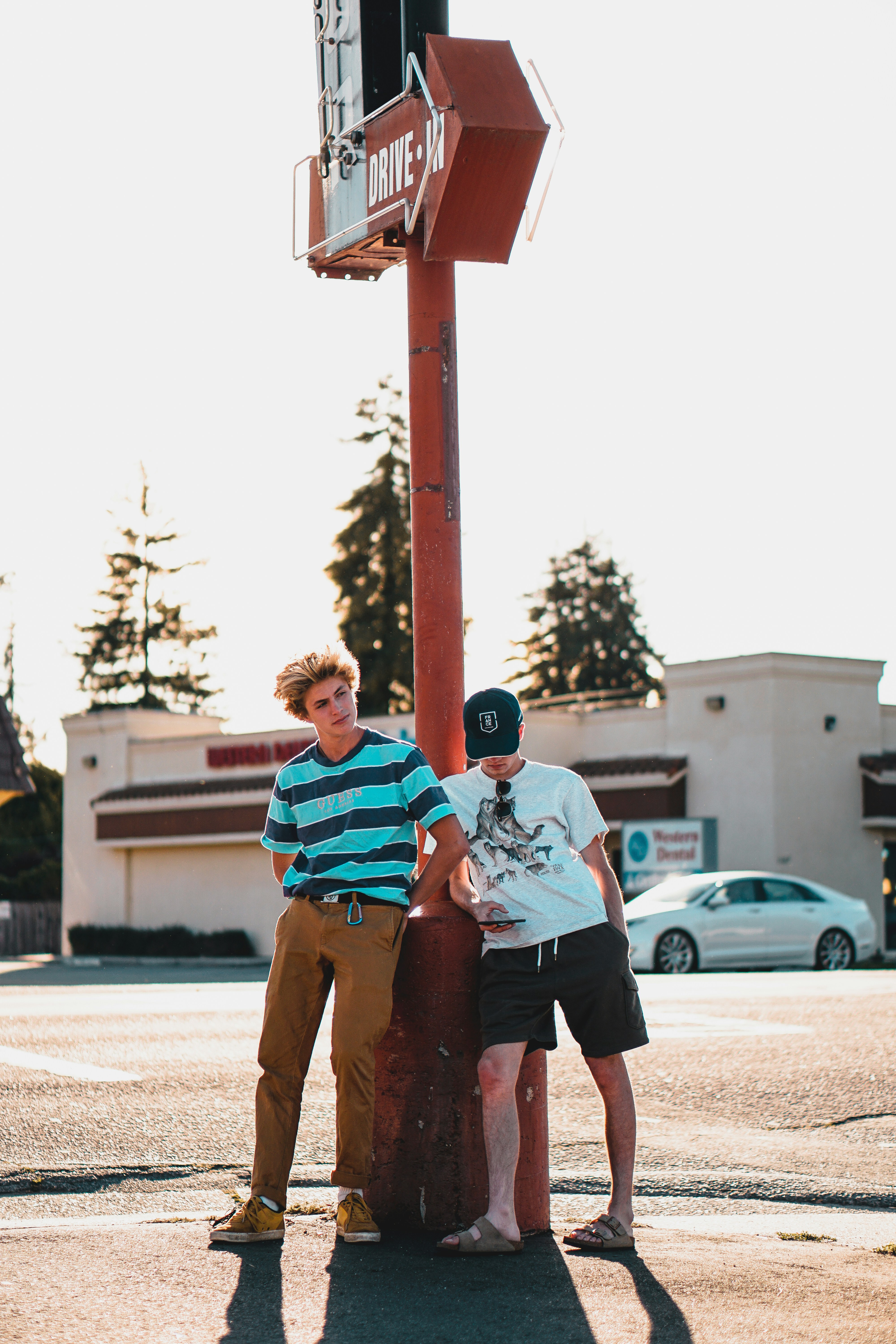 Two man standing and both leaning on red metal post photo – Free People ...