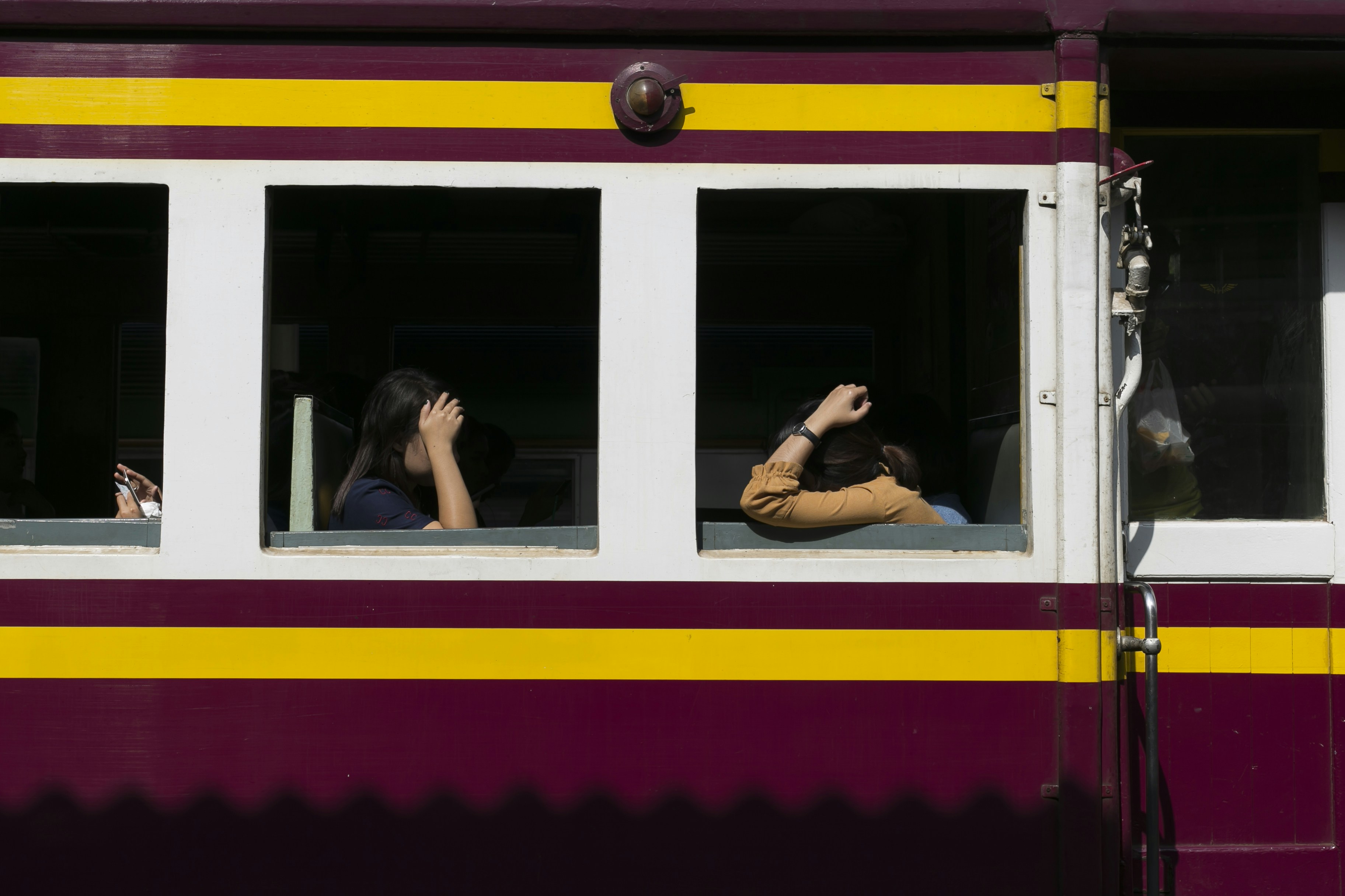 Quiet Portraits Through a Maroon-and-Gold Train Car Window