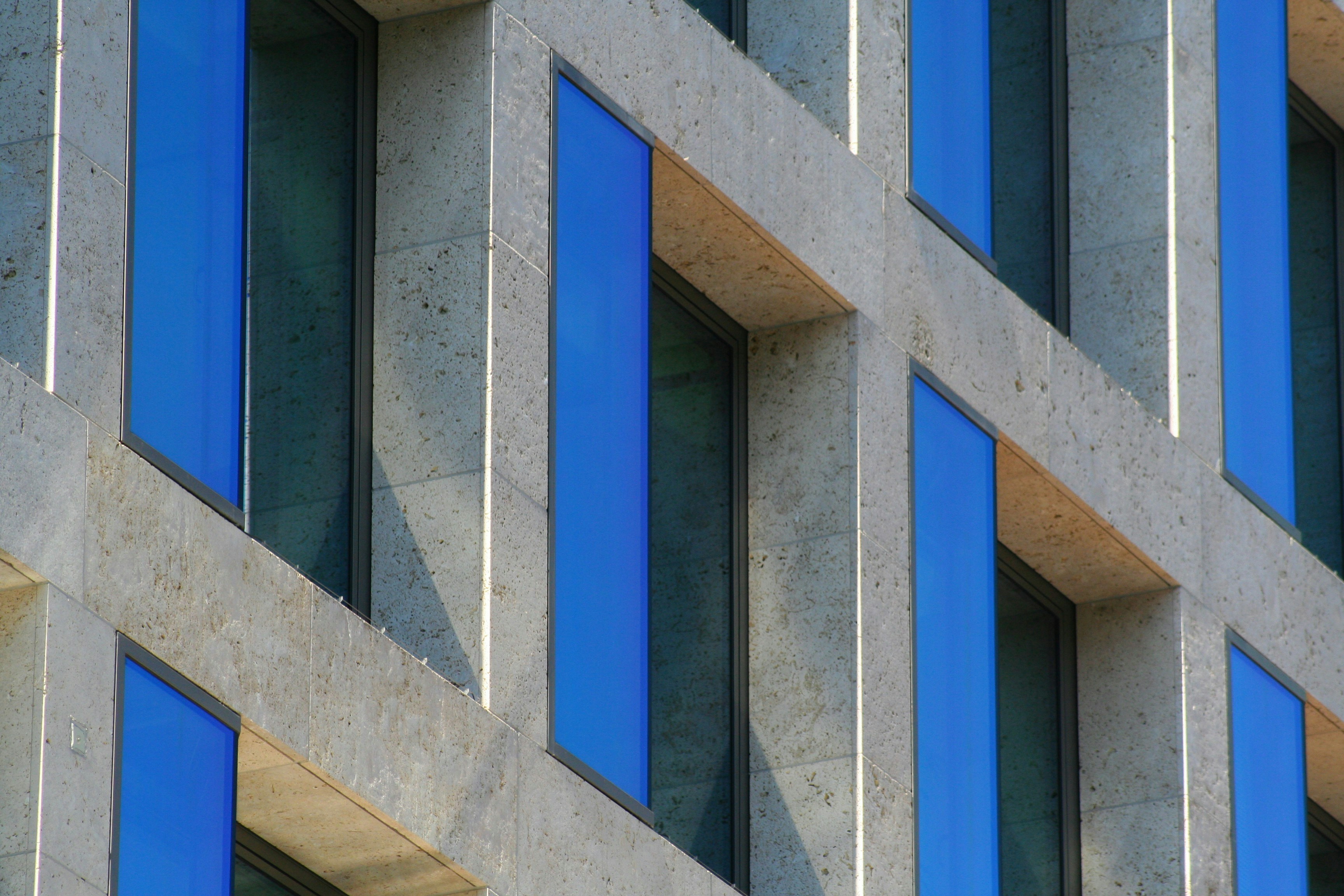 Concrete-framed windows reflecting the vibrant blue sky on a building facade.