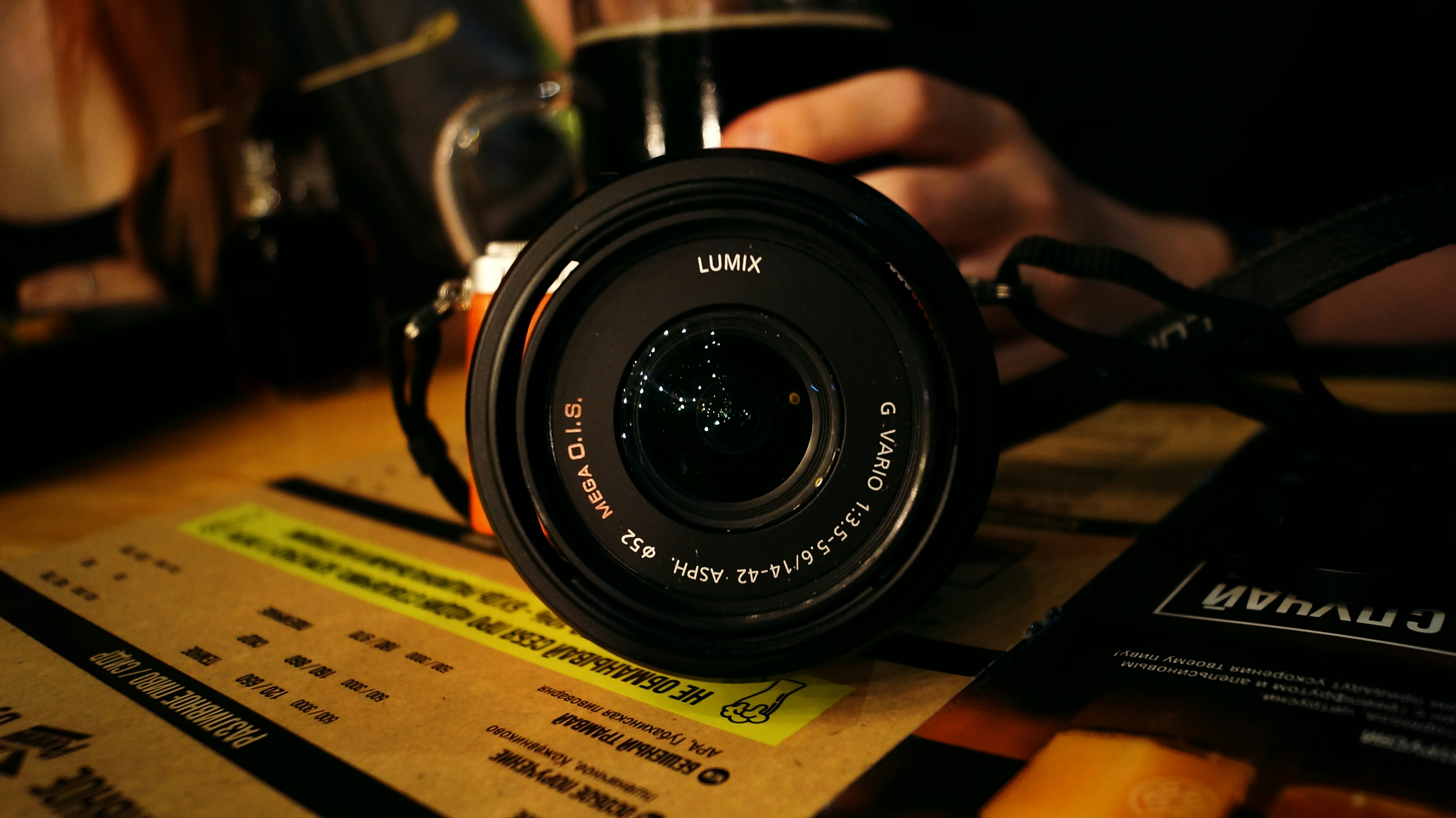 Close-up view of a camera lens resting on a table, showcasing its intricate details amidst a cozy setting.