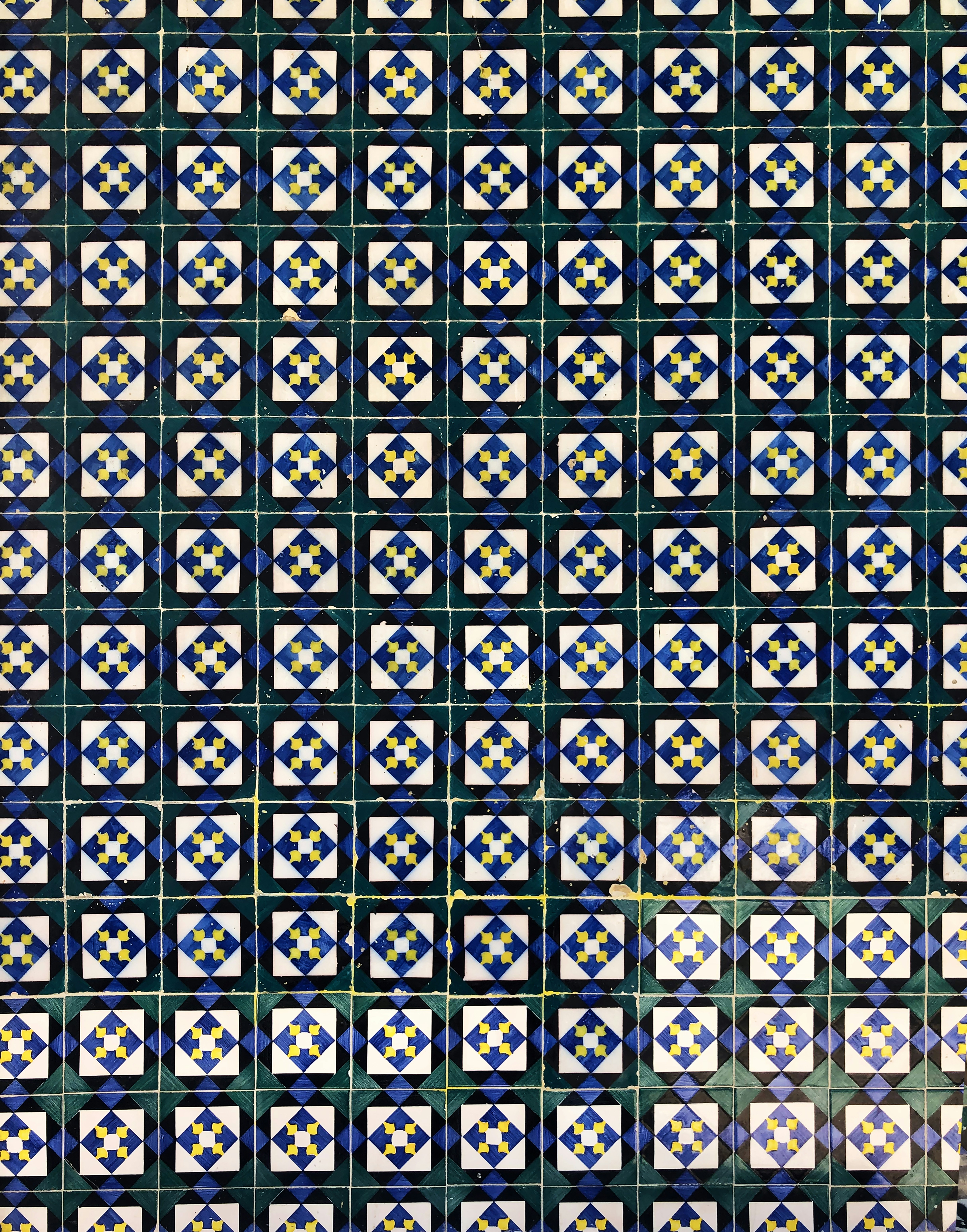 Intricate blue and yellow tiles arranged in a repetitive pattern, showcasing a geometric design. The uniformity creates a visually striking effect.