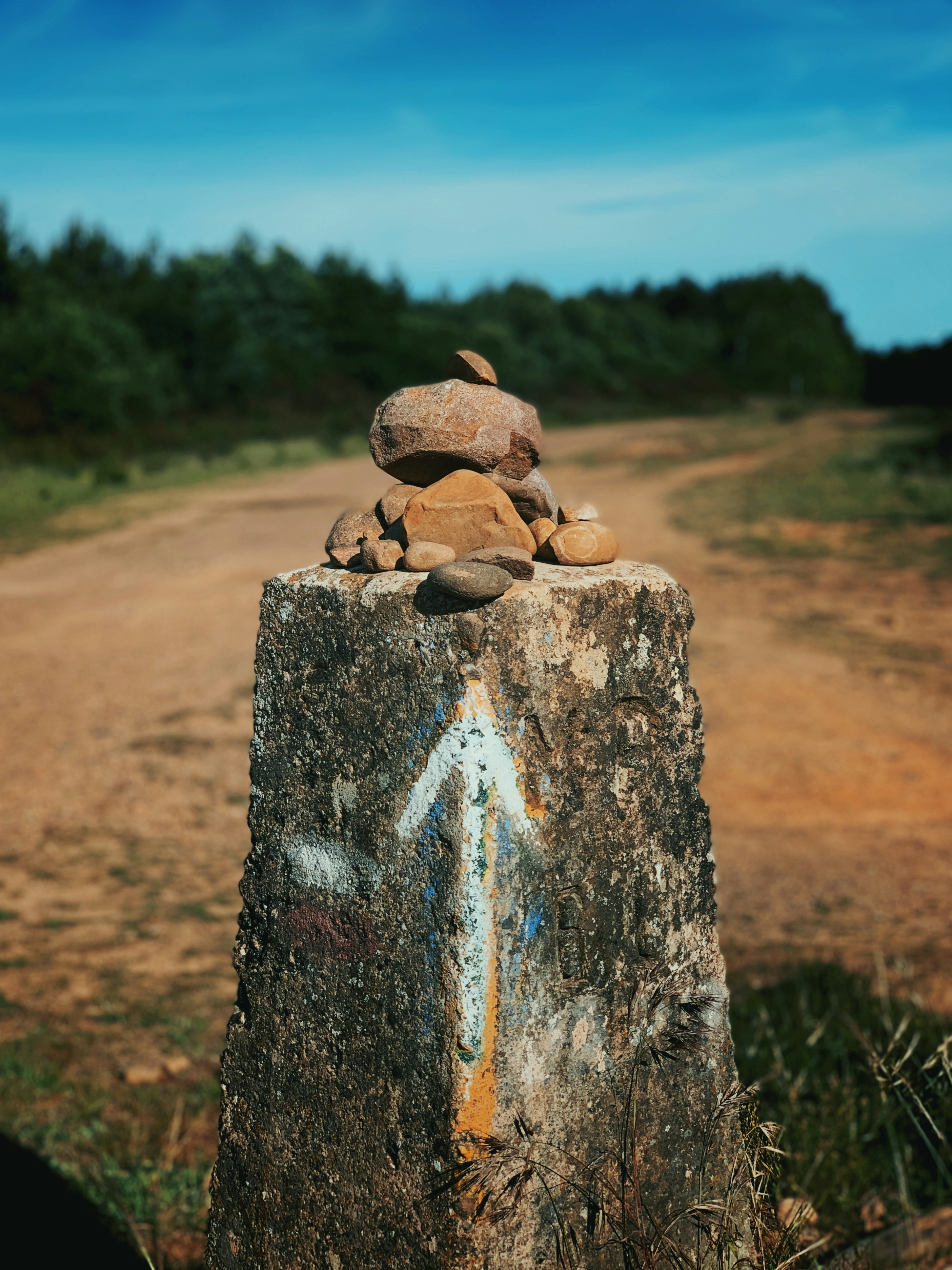 Cairn on a Weathered Marker at a Dusty Trail
