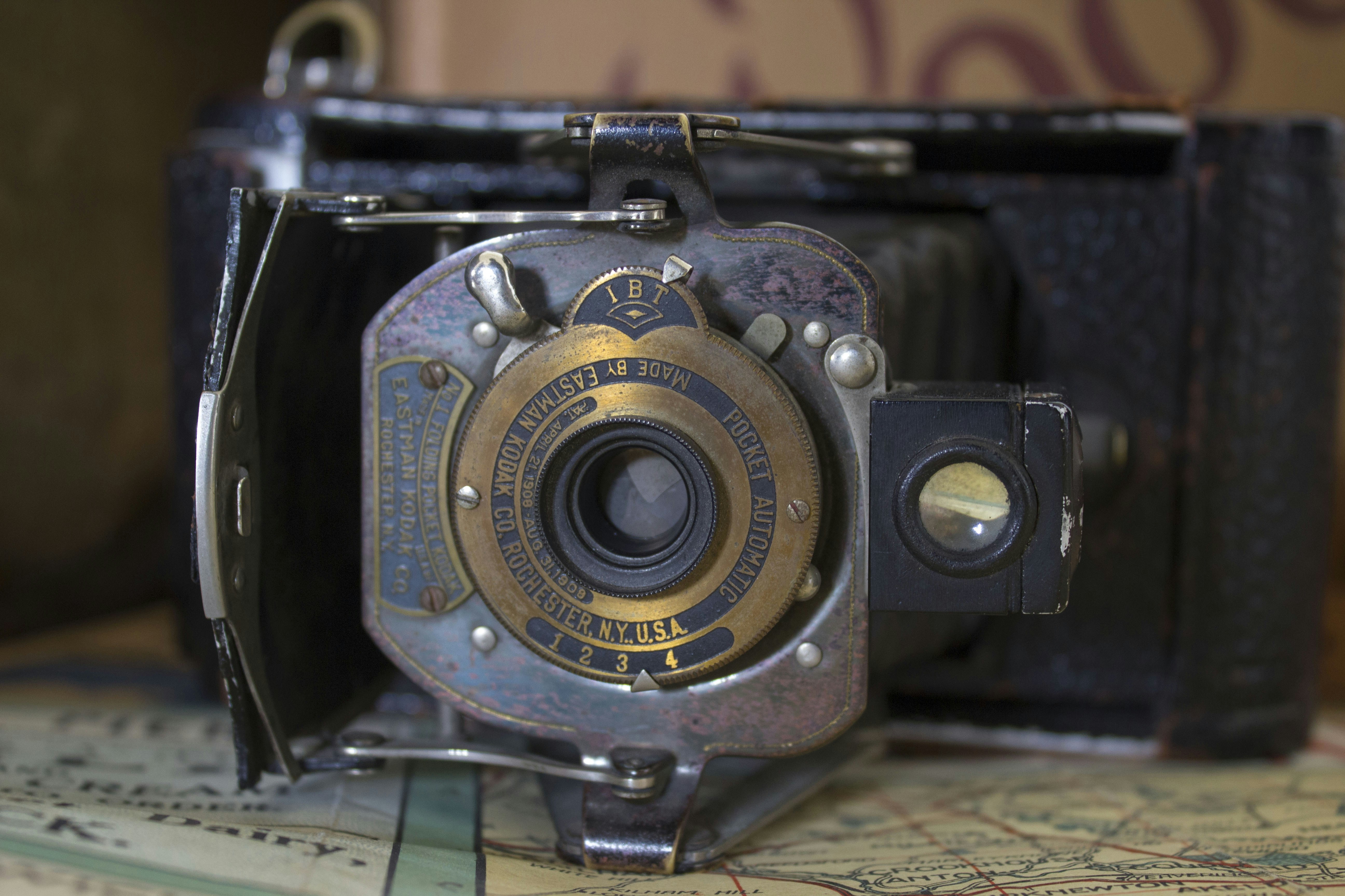 Close-up of an antique camera showcasing intricate details and craftsmanship on a backdrop of vintage maps.