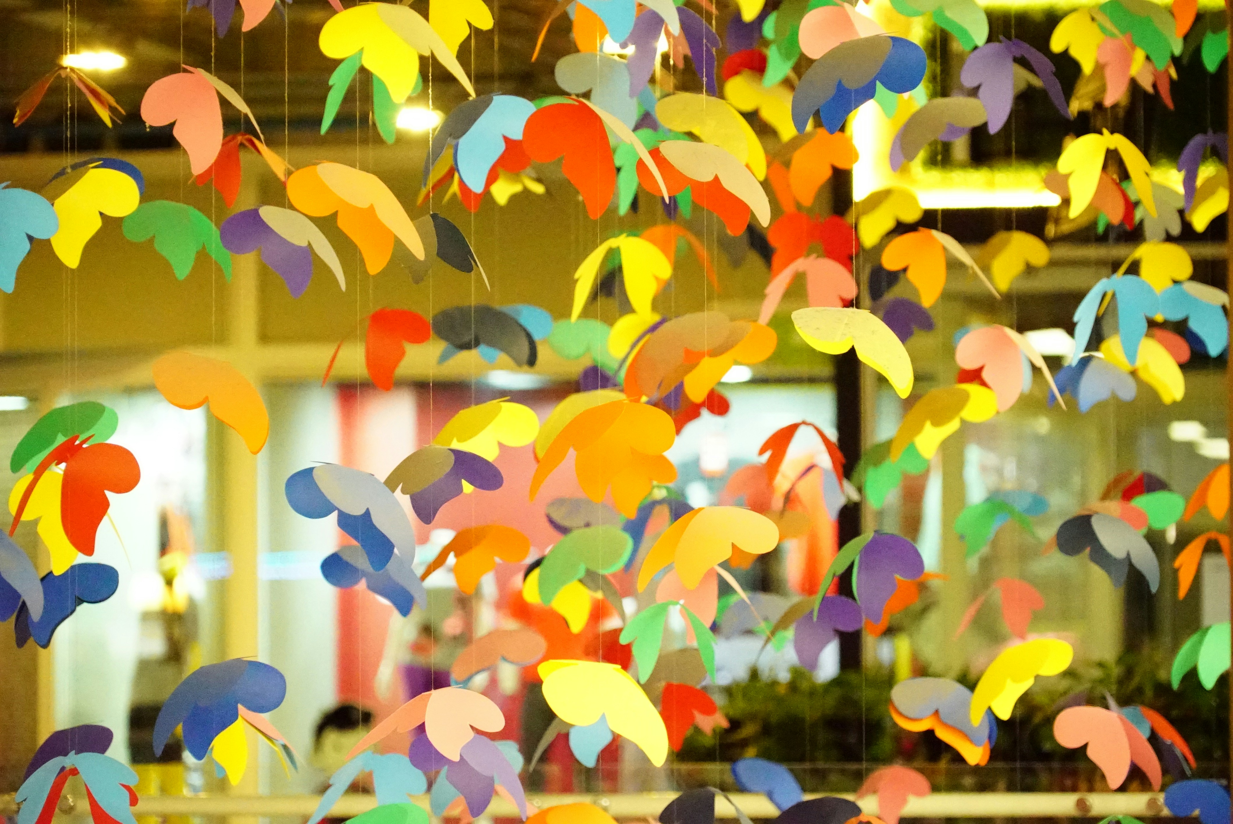 A vibrant display of hanging paper petals in various colors, creating a playful atmosphere in a modern space.