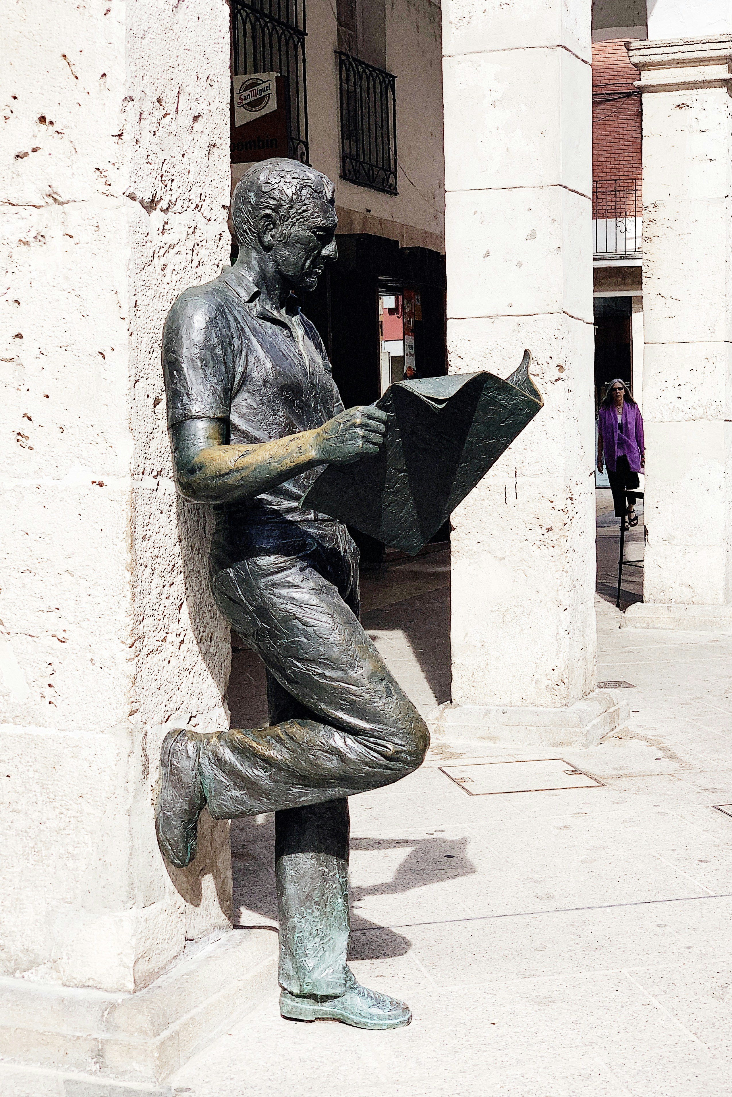 Statue in Motion: A Bronze Reader Paused by a Newsprint in Stone